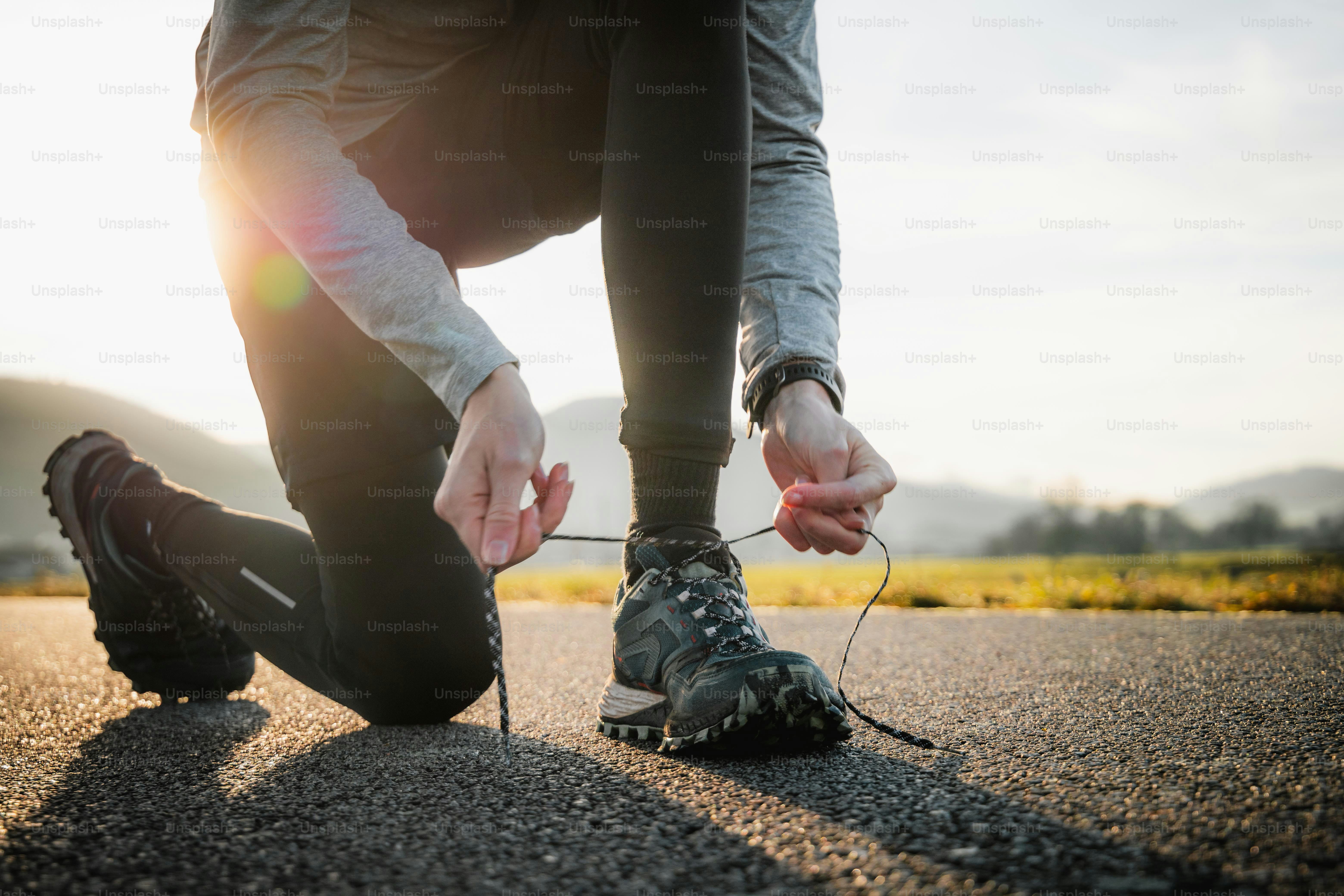 Une personne attachant un lacet sur une route photo – Image de Attacher ...