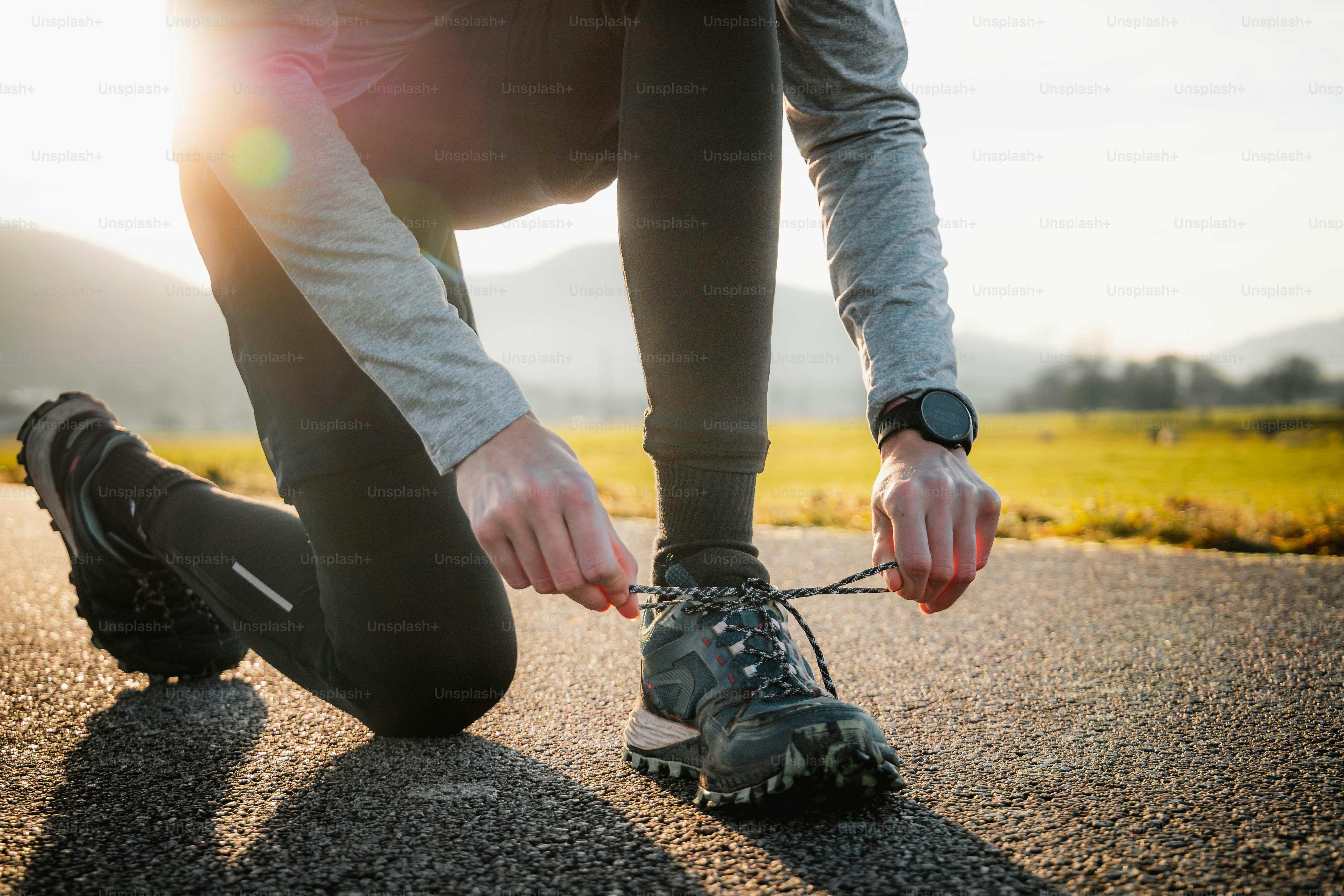 A person tying their shoe laces on a road photo – Male Image on Unsplash
