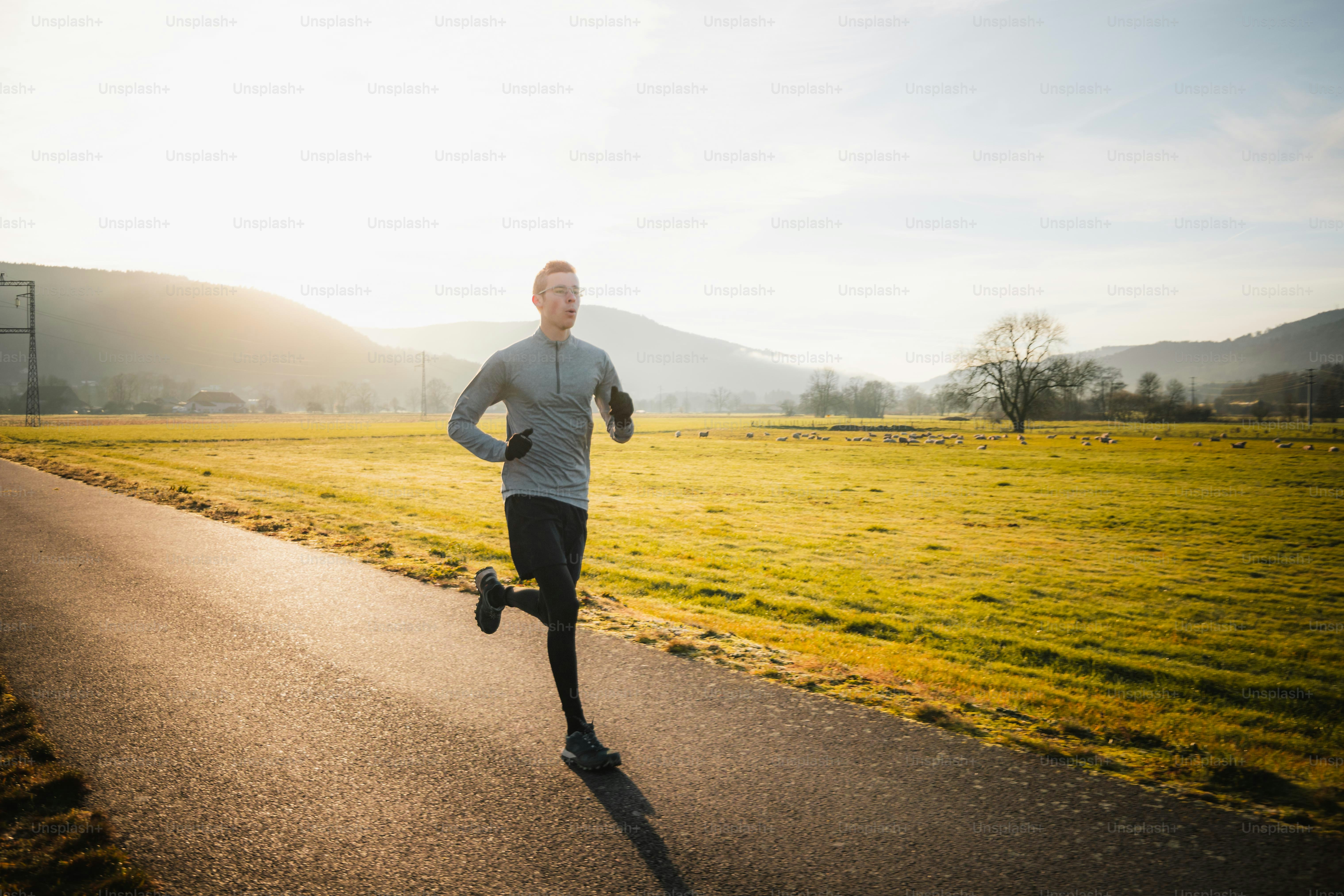 A man running down a road in the middle of a field photo – Male Image ...