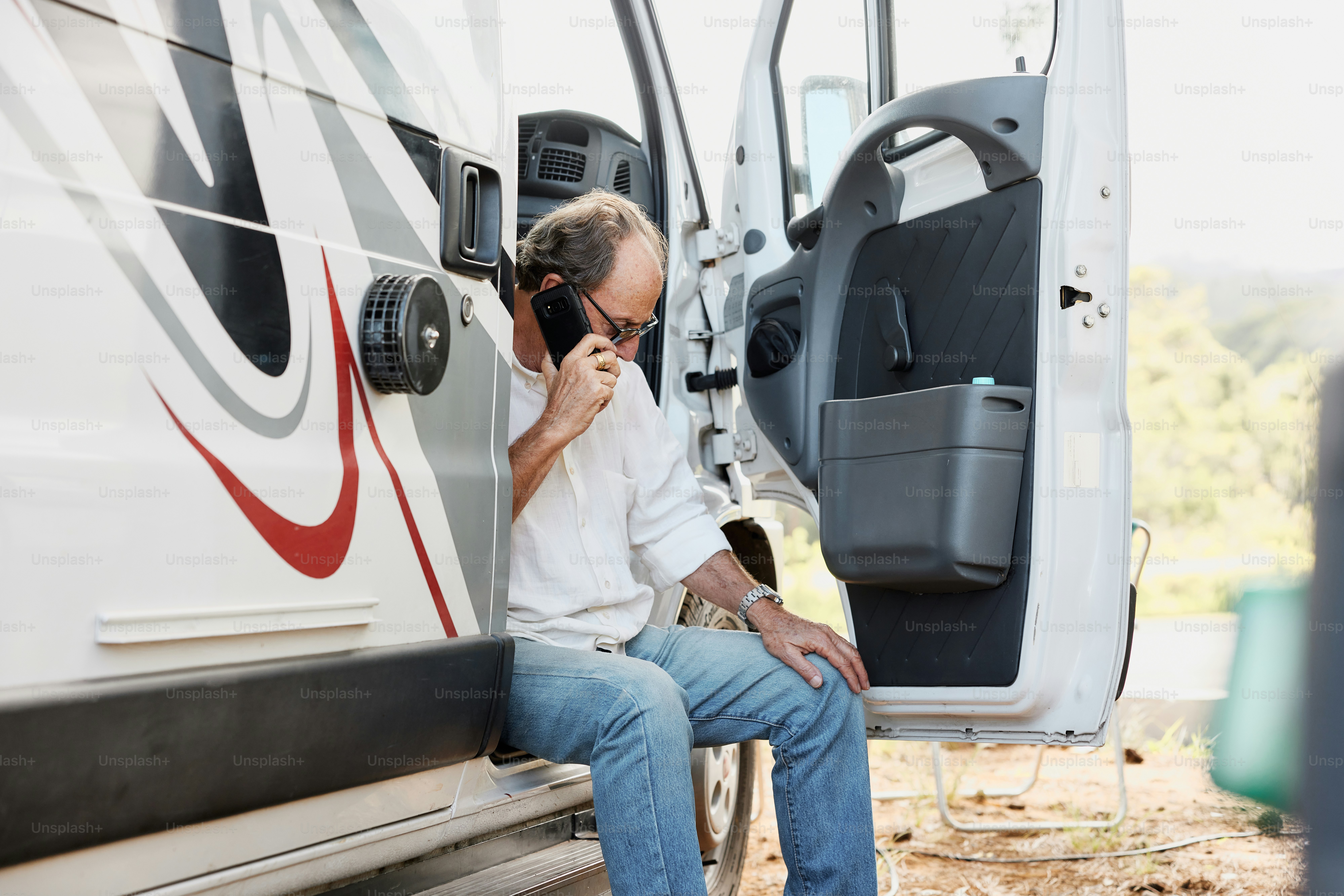 Un homme assis sur le côté d’un camion parlant au téléphone portable ...