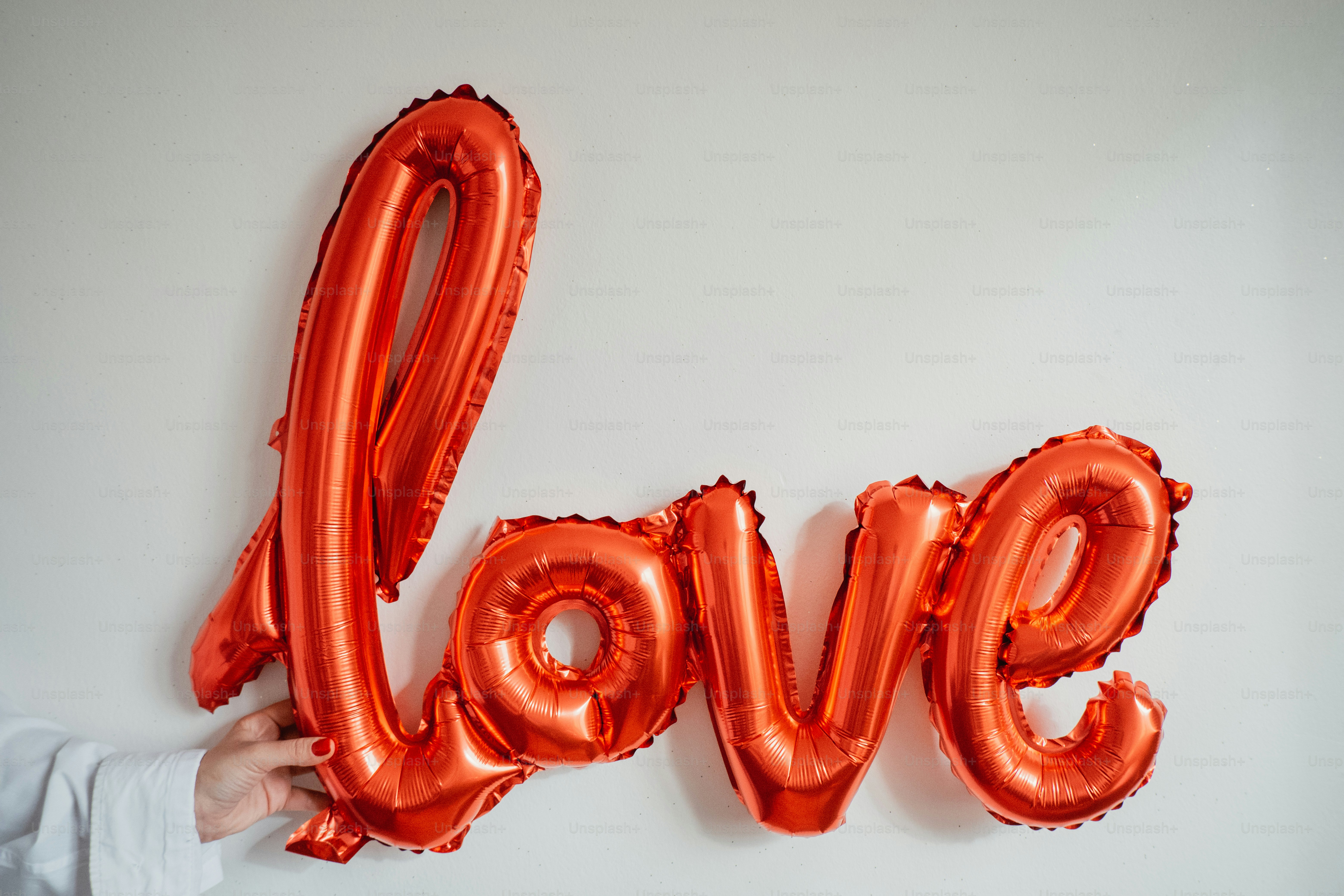 A person holding a red balloon in the shape of the word love photo ...