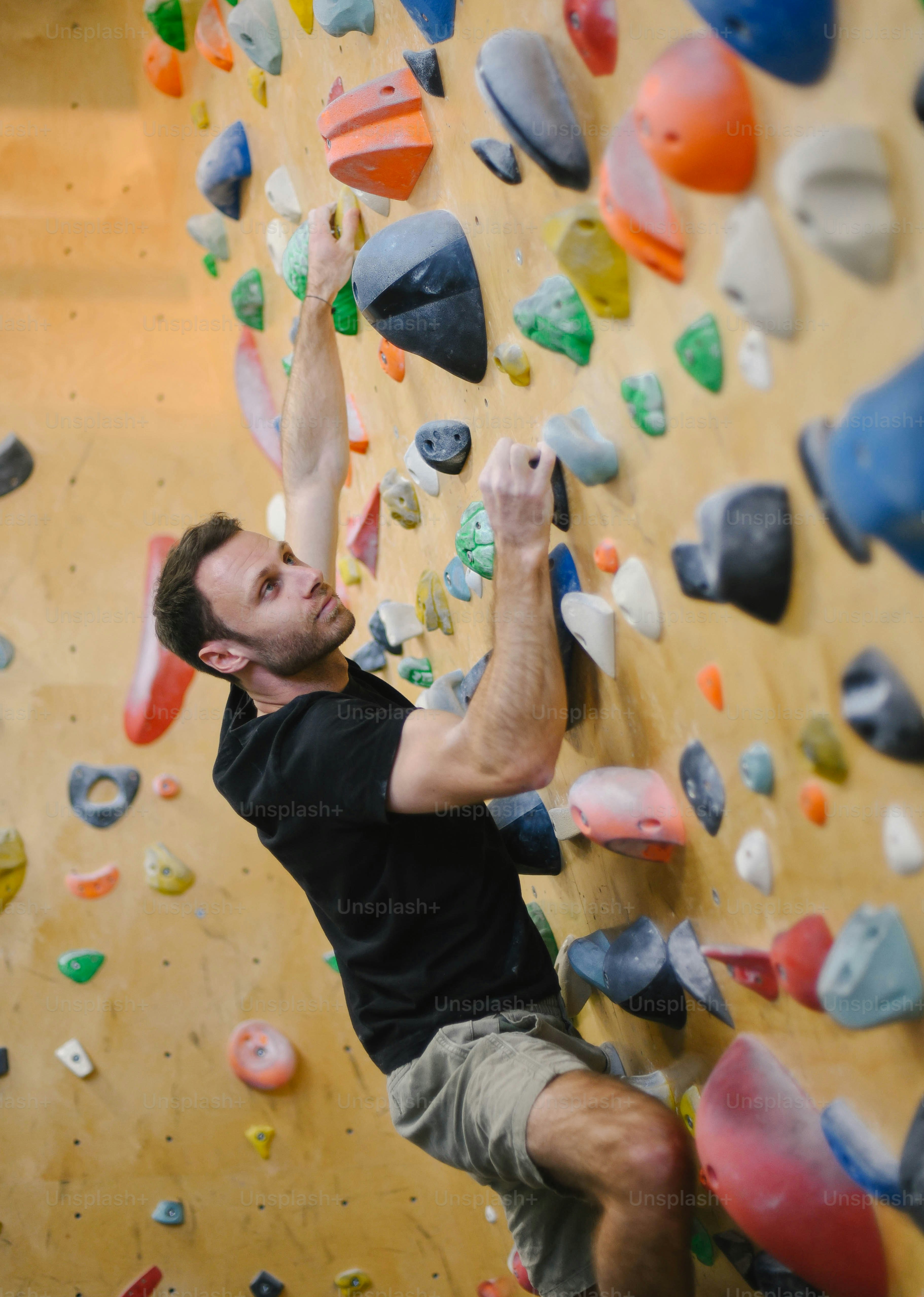 A man holding his hand up to a climbing wall photo – Bouldering wall ...