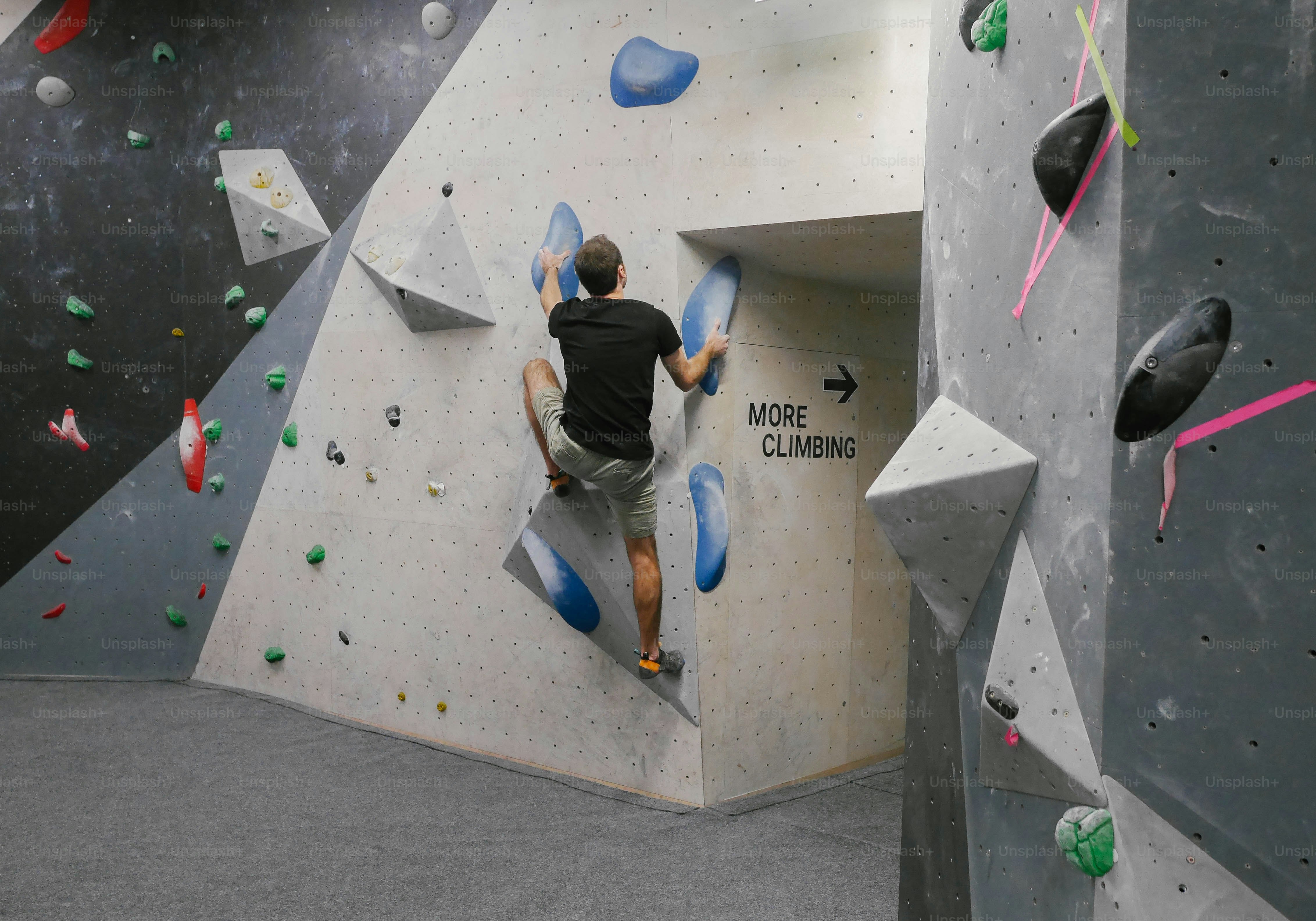 A man climbing up the side of a climbing wall photo – Bouldering Image ...