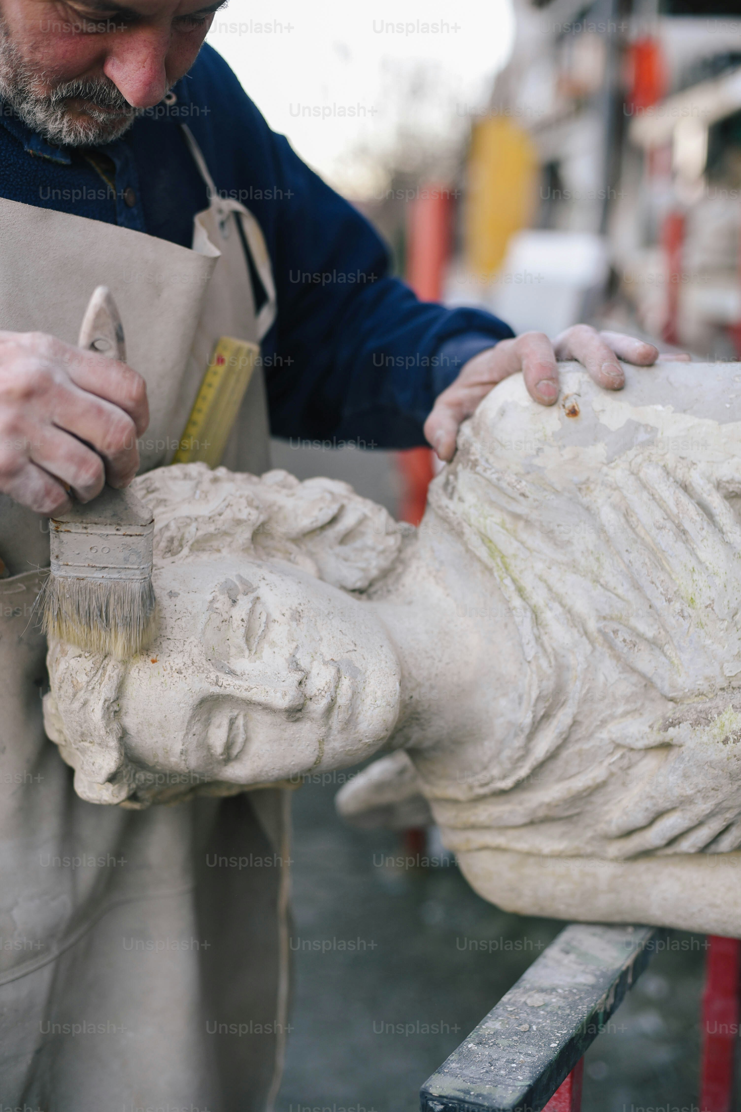 A man is working on a statue with a piece of wood photo – Art Image on ...