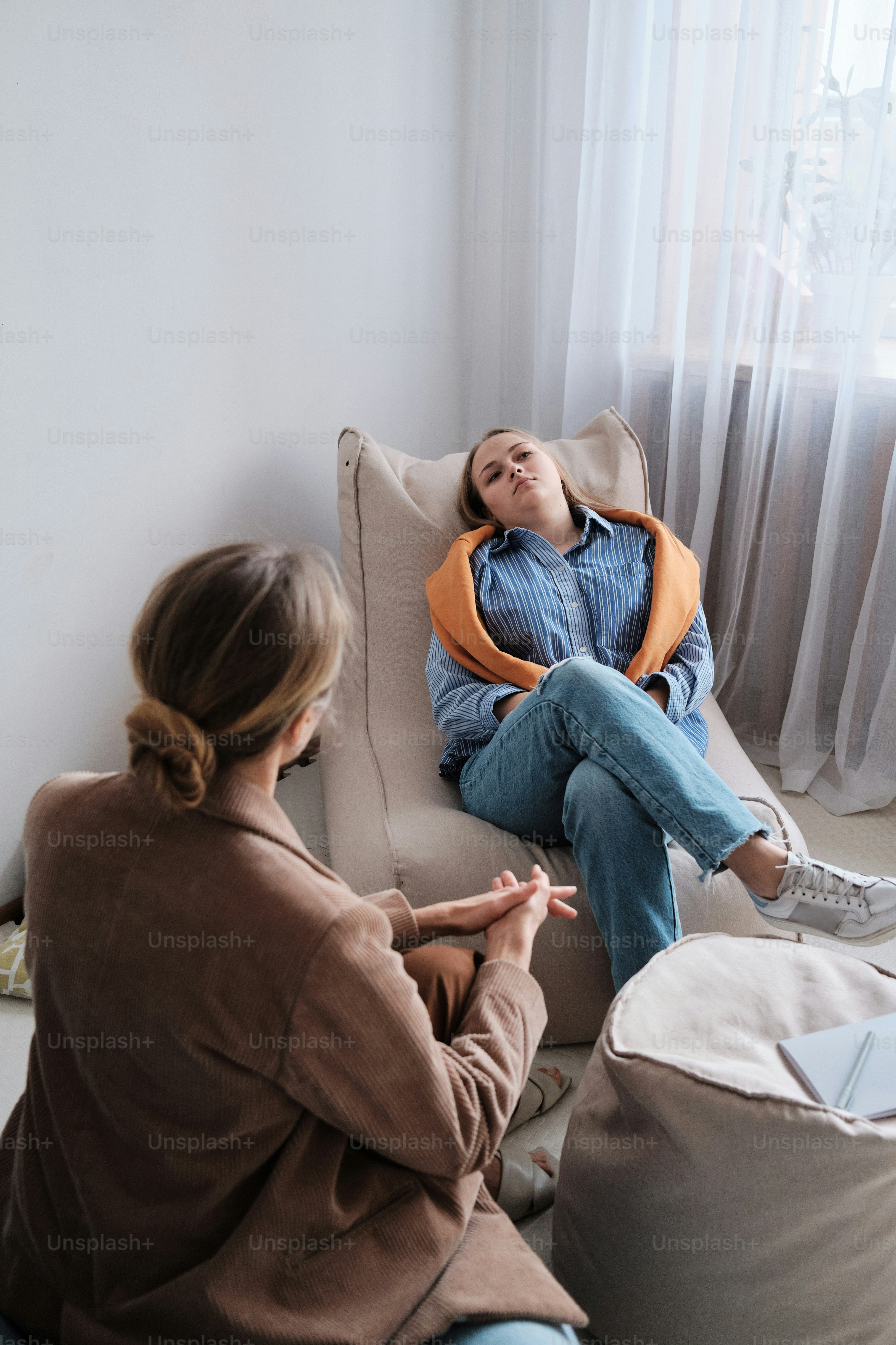 A woman sitting on a bean bag chair talking to another woman photo ...