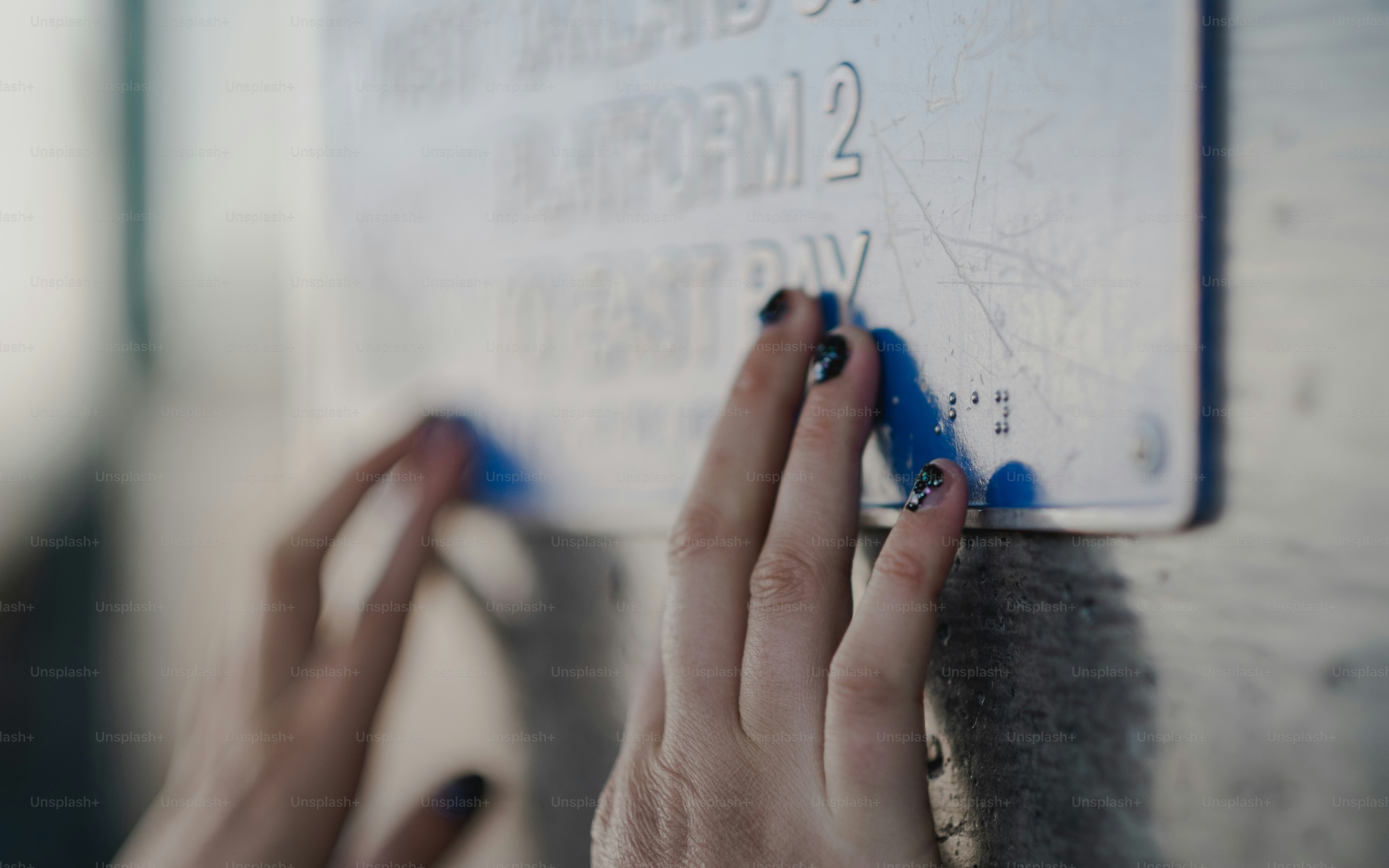 A person is writing on a sign on a wall photo – Accessibility Image on ...