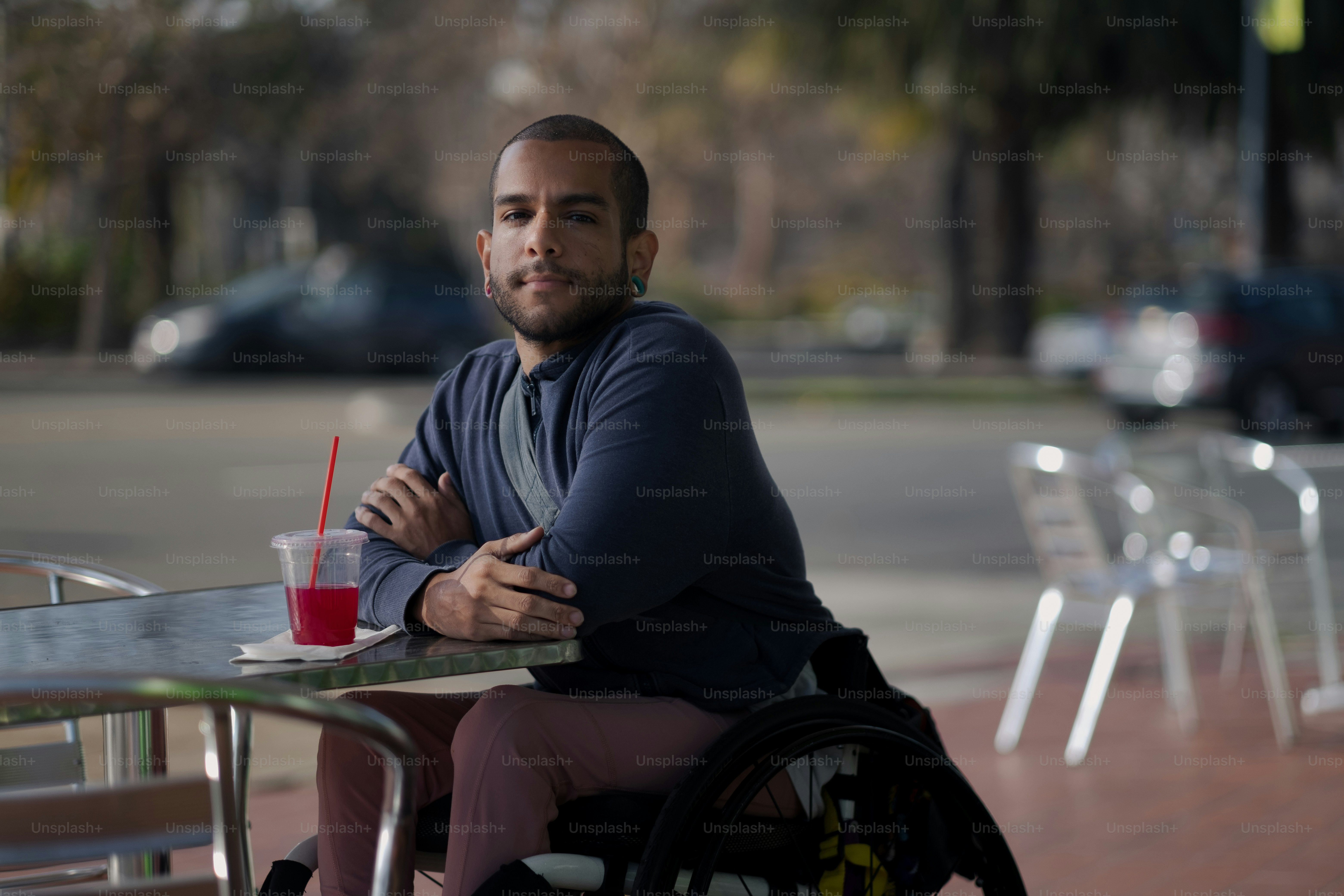 A man sitting at a table with his arms crossed photo – Disability Image ...