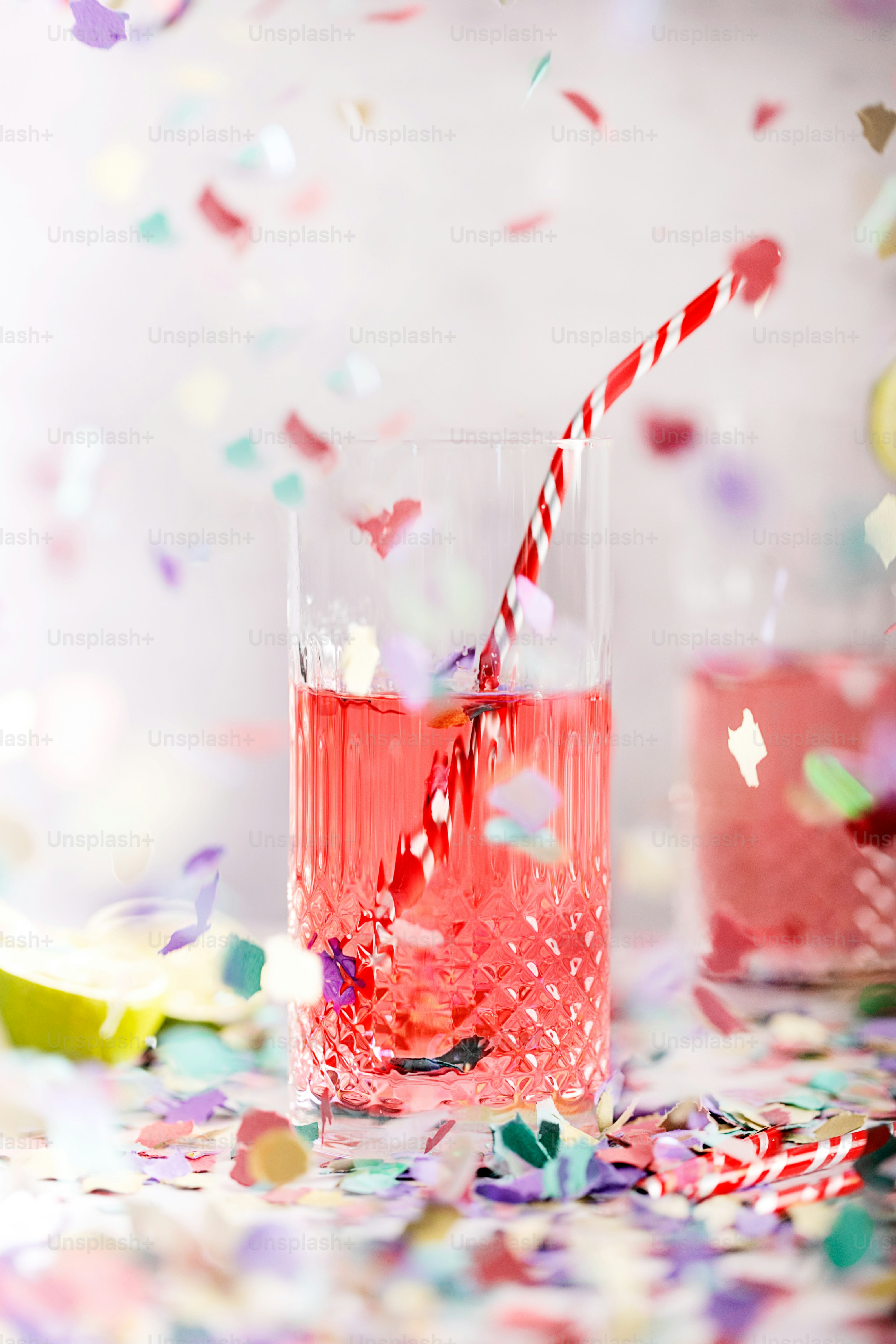 A pink drink with a straw in it surrounded by confetti photo – Cocktail ...