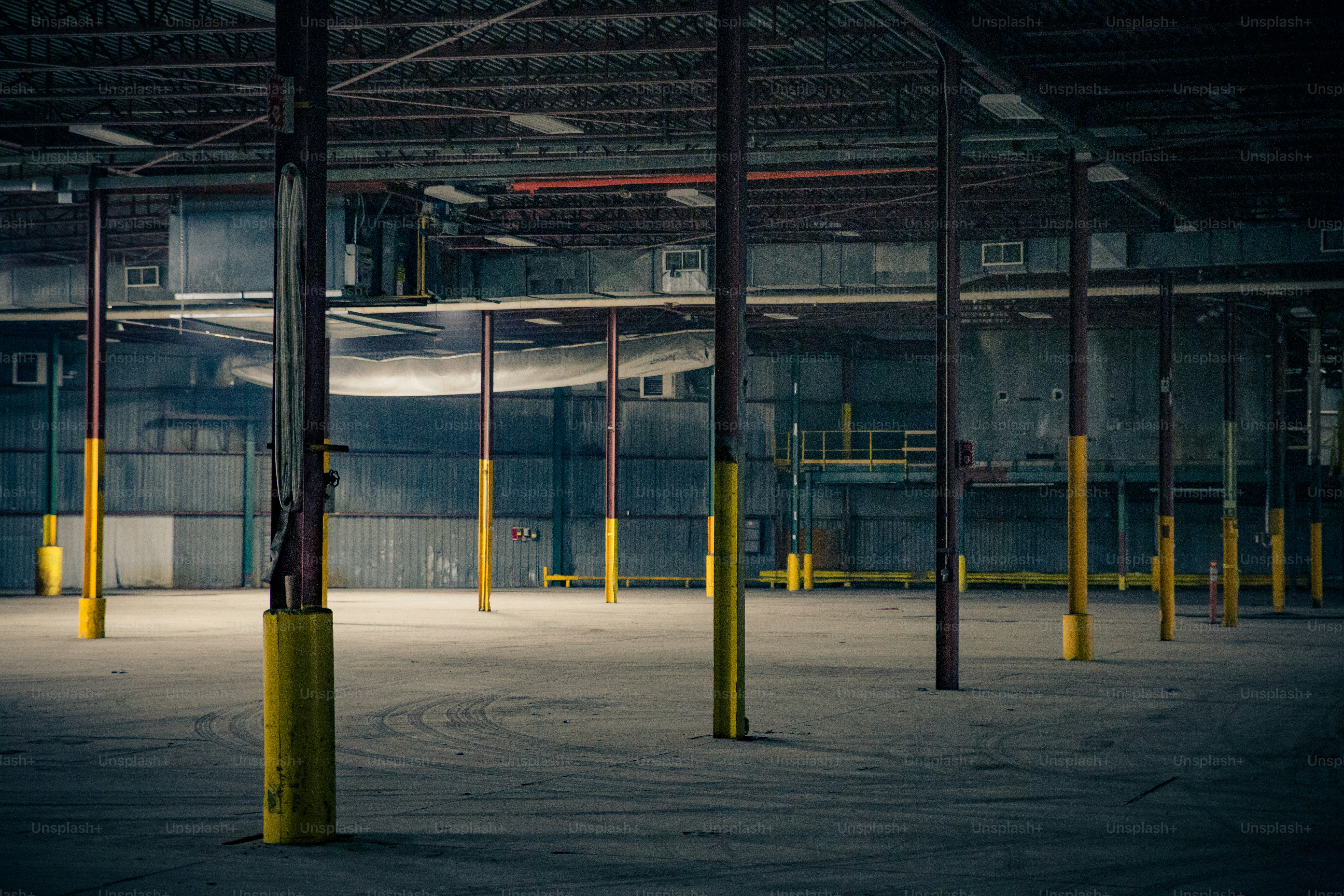 An empty warehouse with yellow poles and yellow posts photo – Factory ...