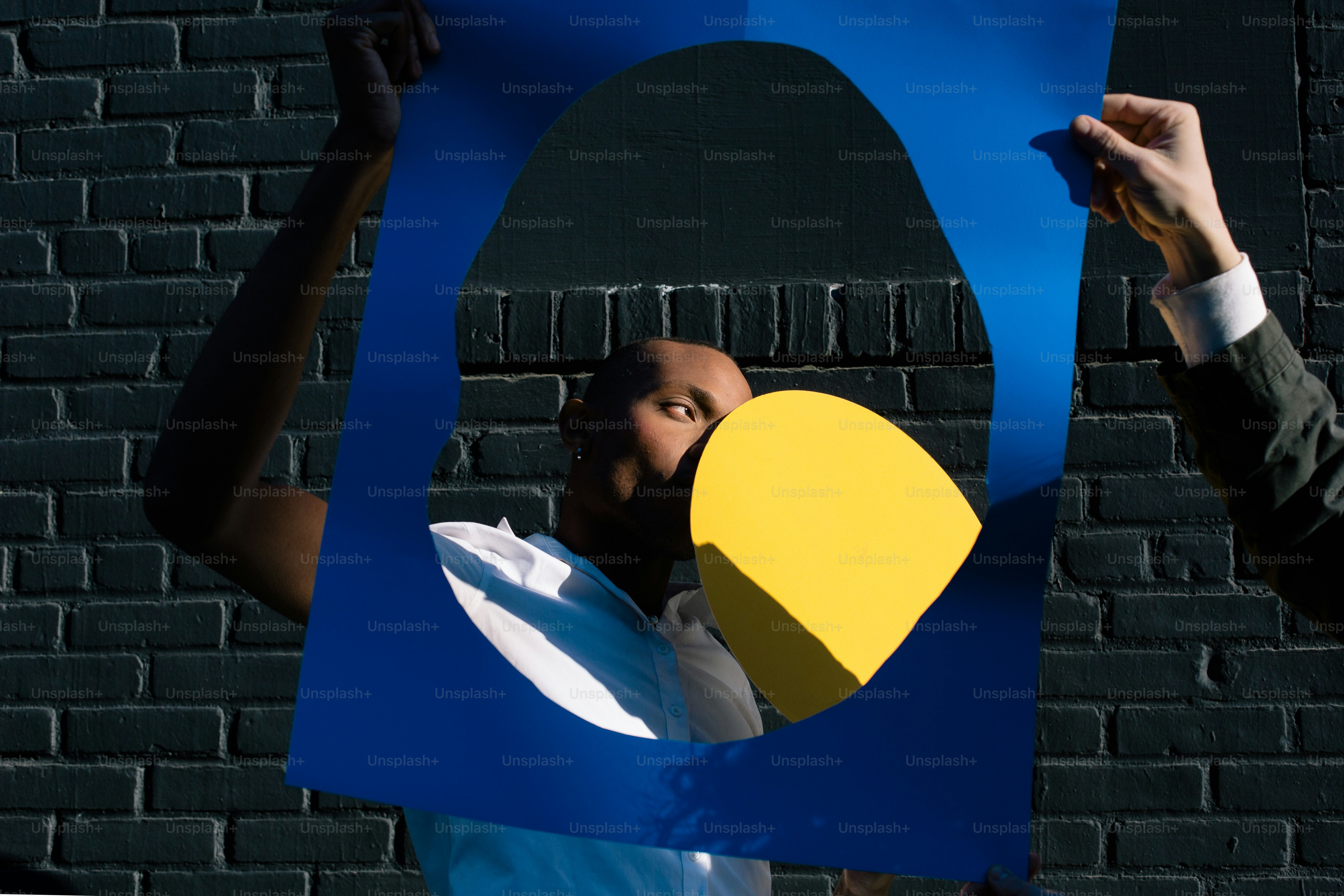 A man holding a large yellow and blue object photo – Portrait Image on ...