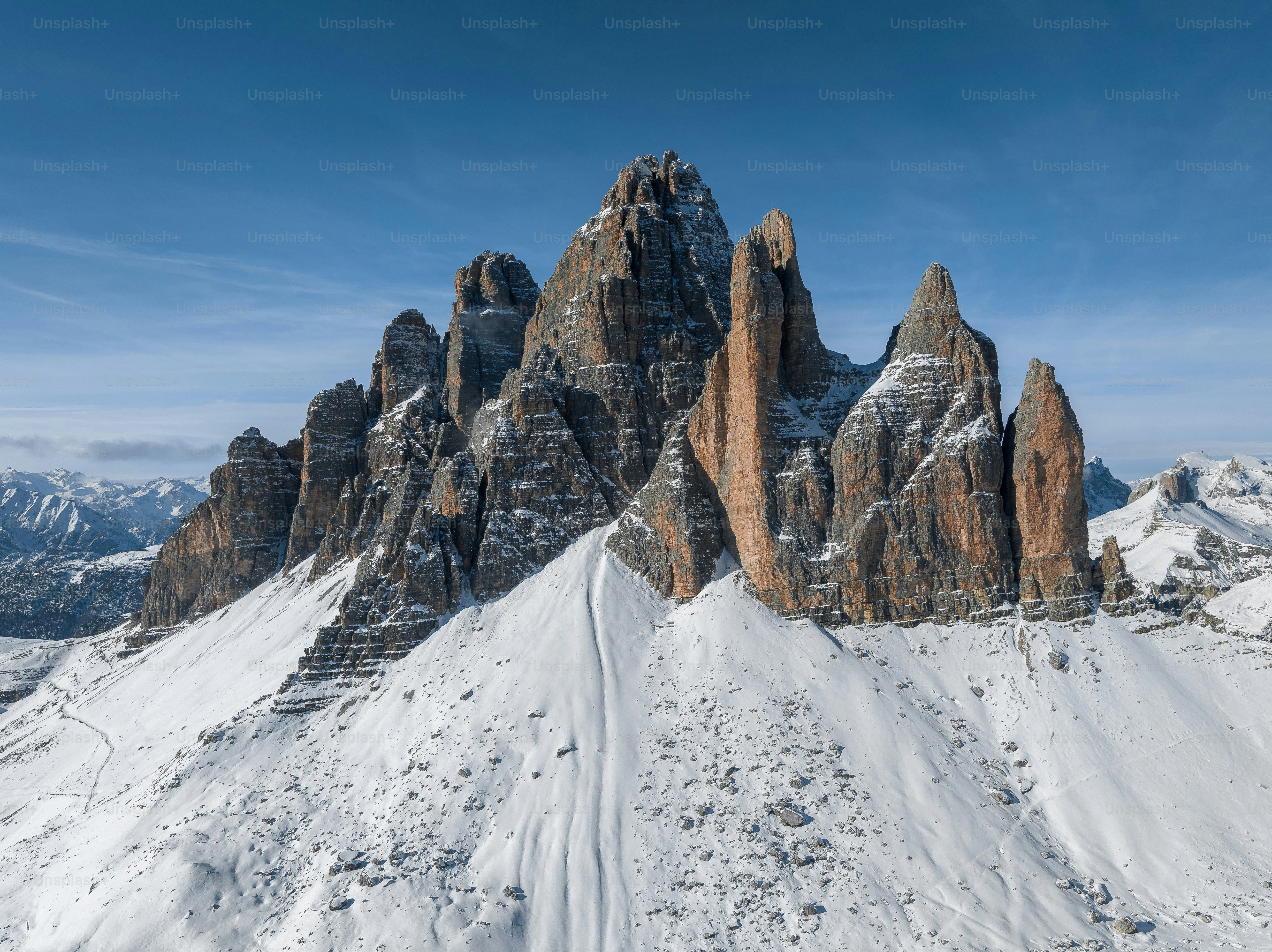 A mountain range covered in snow under a blue sky photo – Abyss Image ...