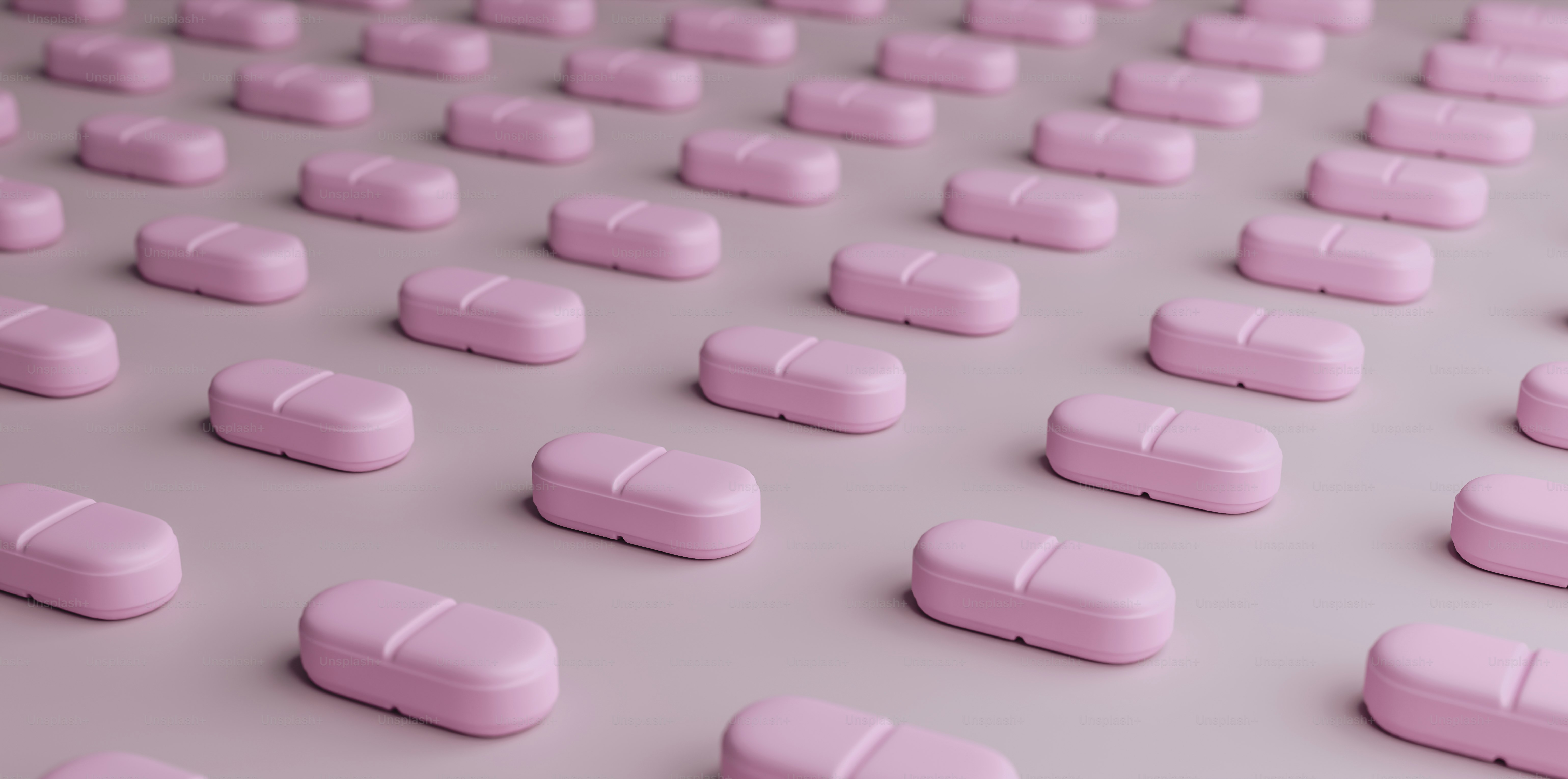 A large group of pink pills sitting on top of a table photo ...