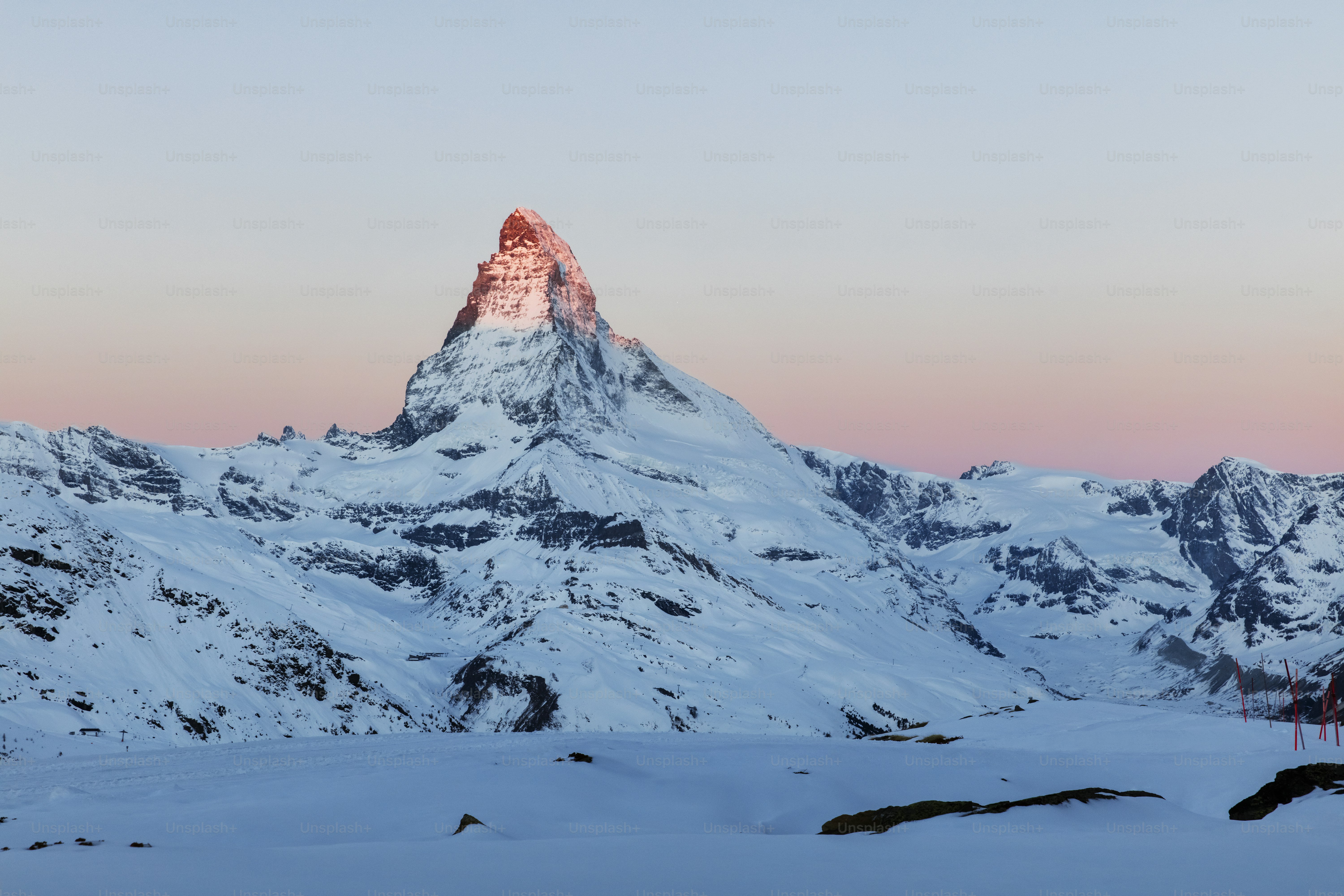 A snow covered mountain with a pink sky in the background photo ...