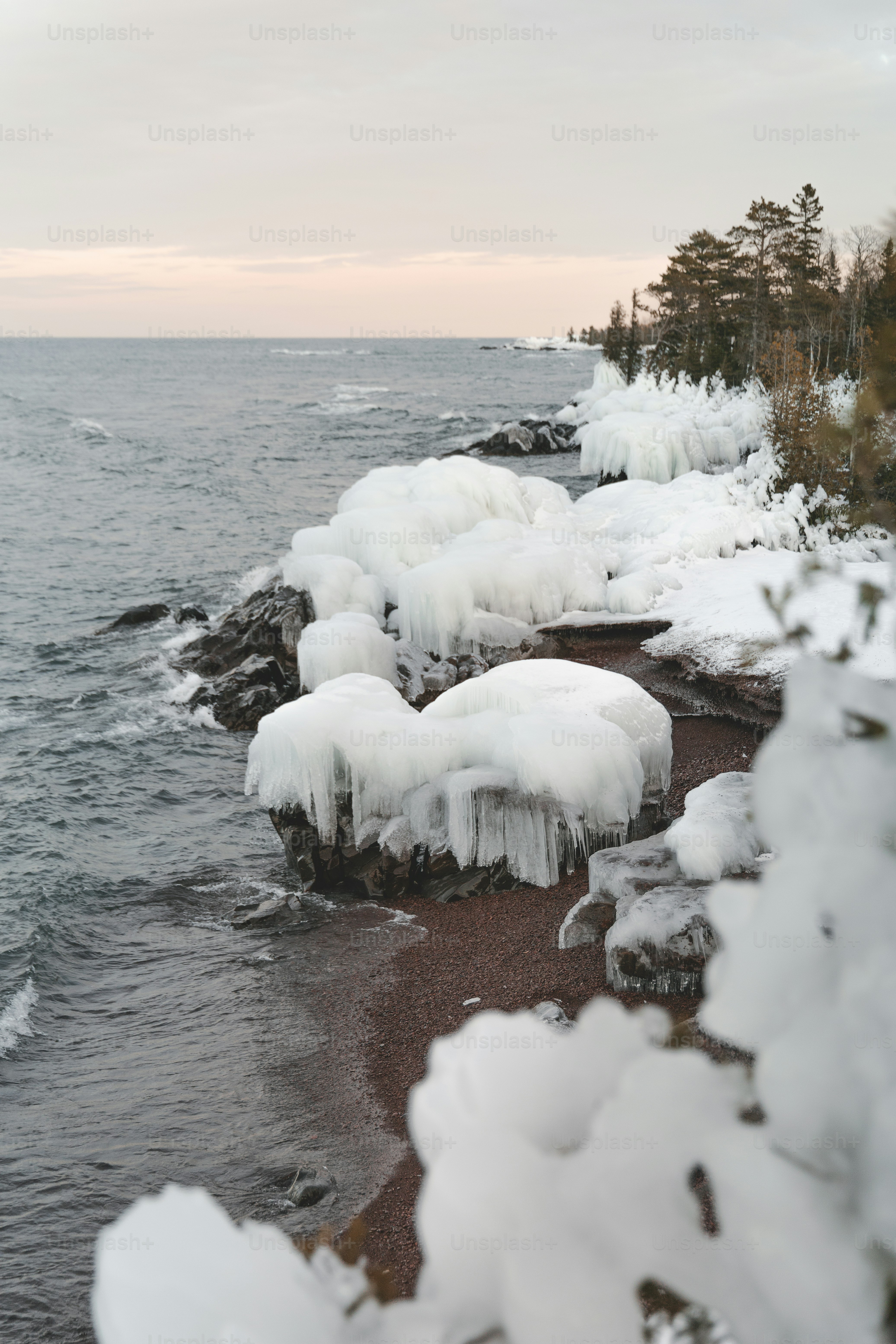 A beach covered in snow next to the ocean photo – Cold water Image on ...