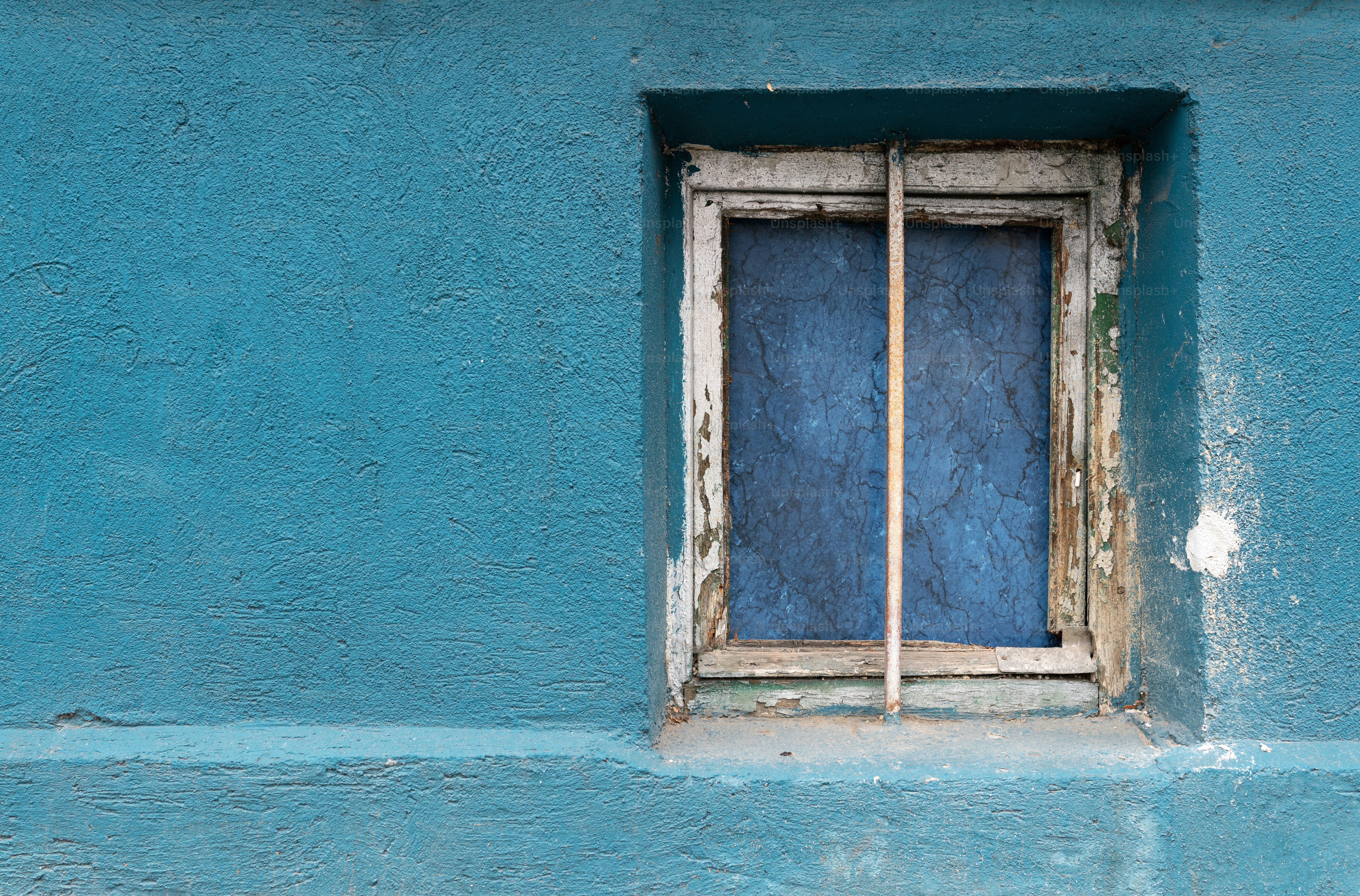 A blue wall with a window and a stick sticking out of it photo – Sofia ...