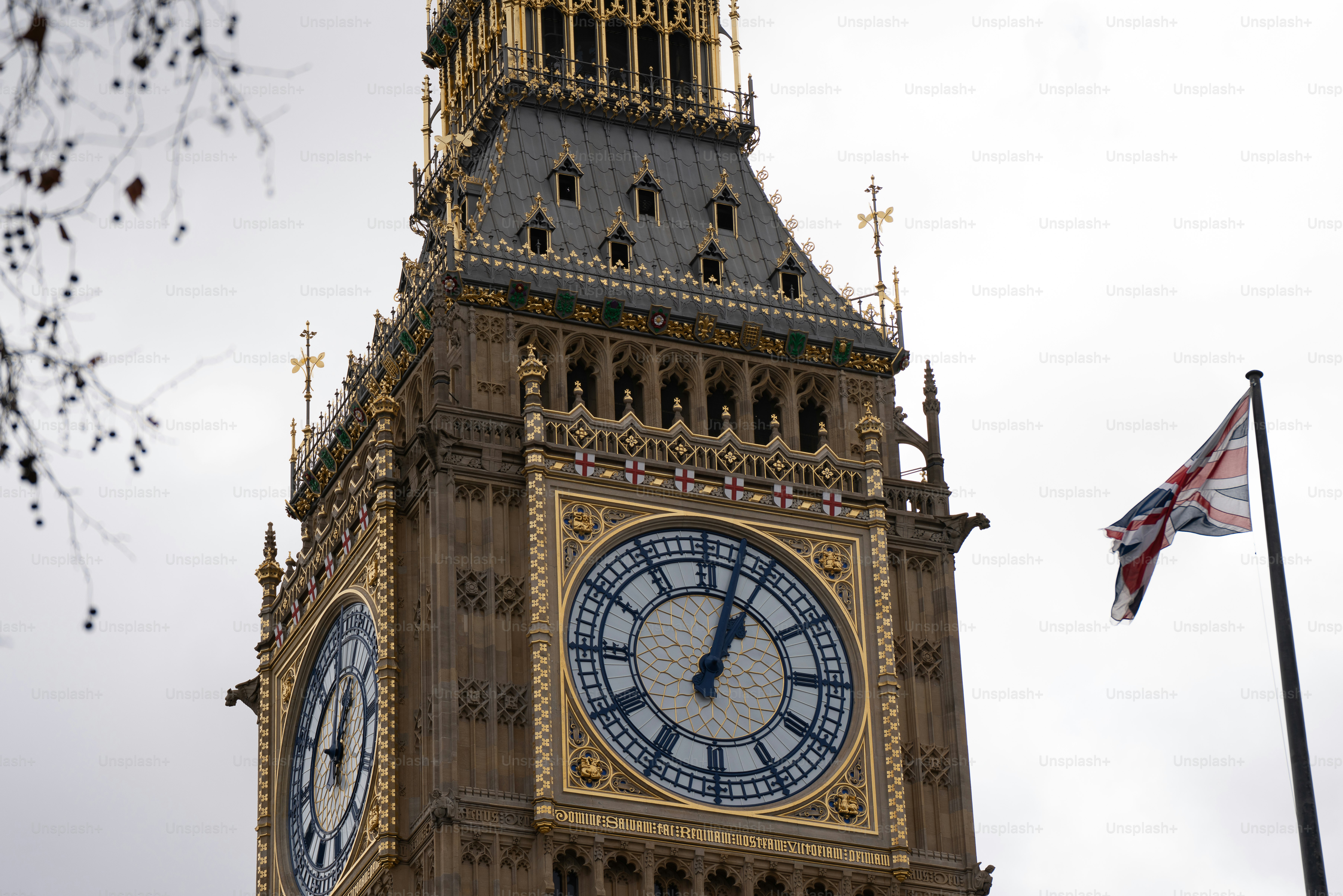 A clock tower with a british flag flying in the background photo ...