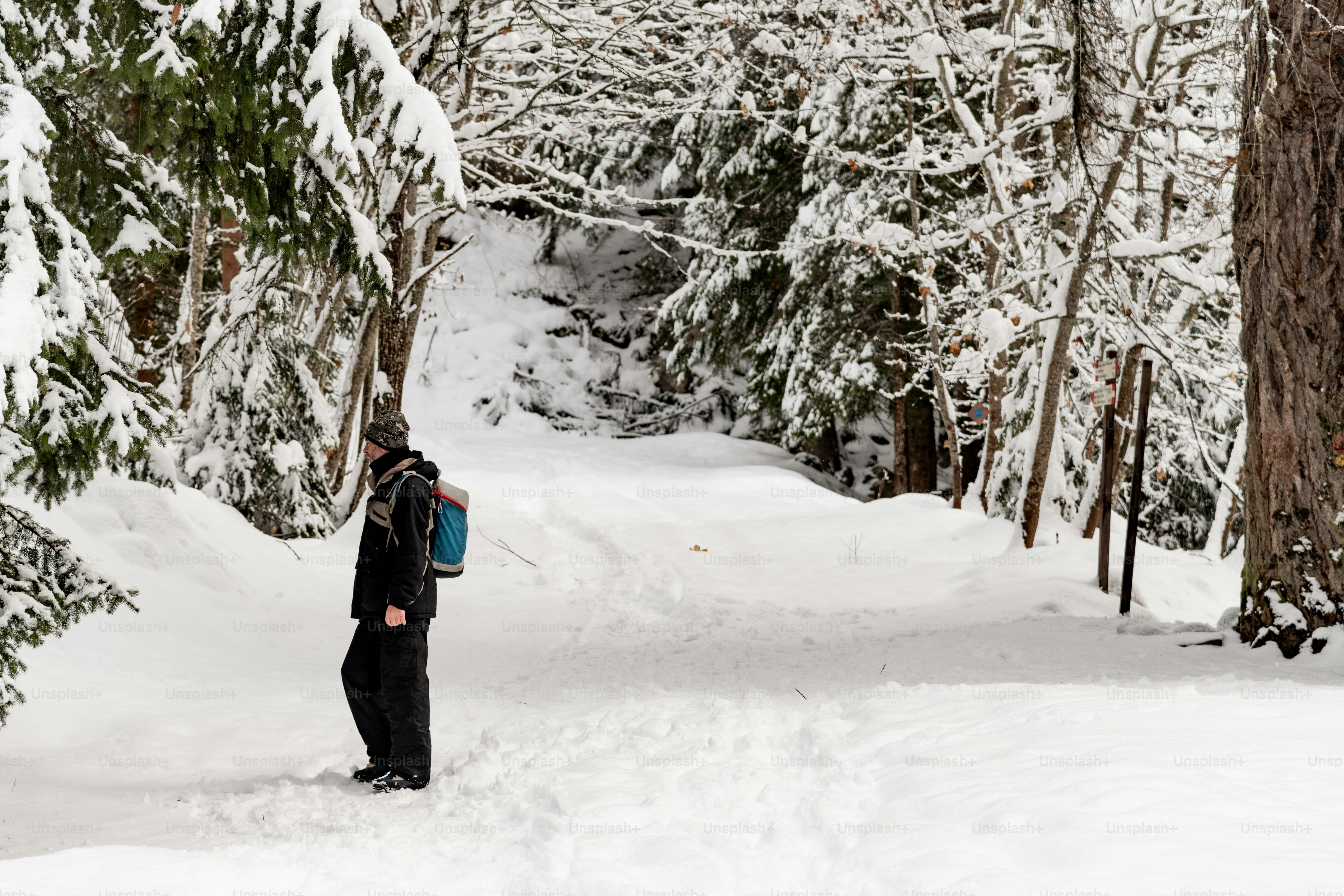 A person walking through the snow carrying a backpack photo – Snow ...