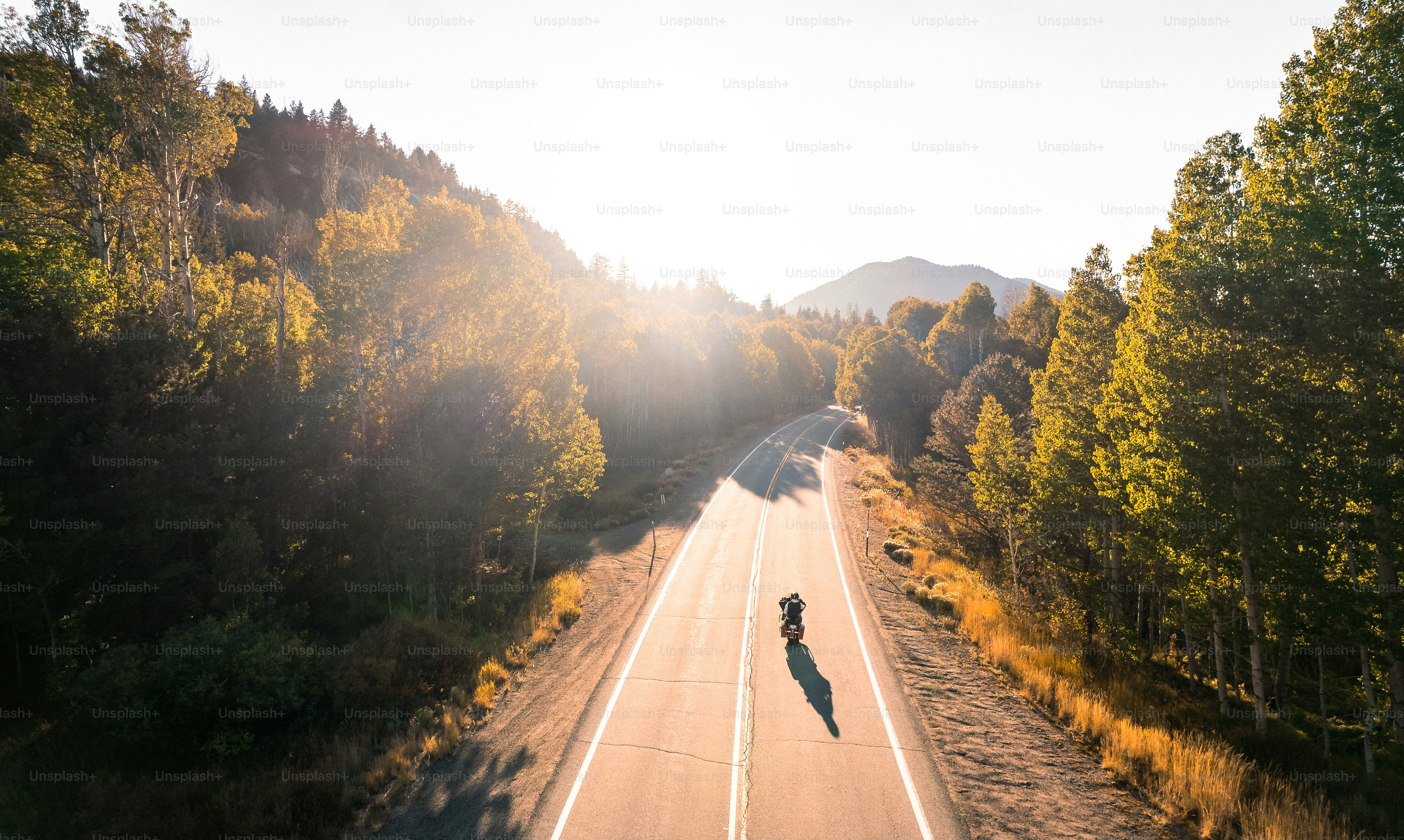 A person riding a motorcycle down the middle of a road photo – Lake ...