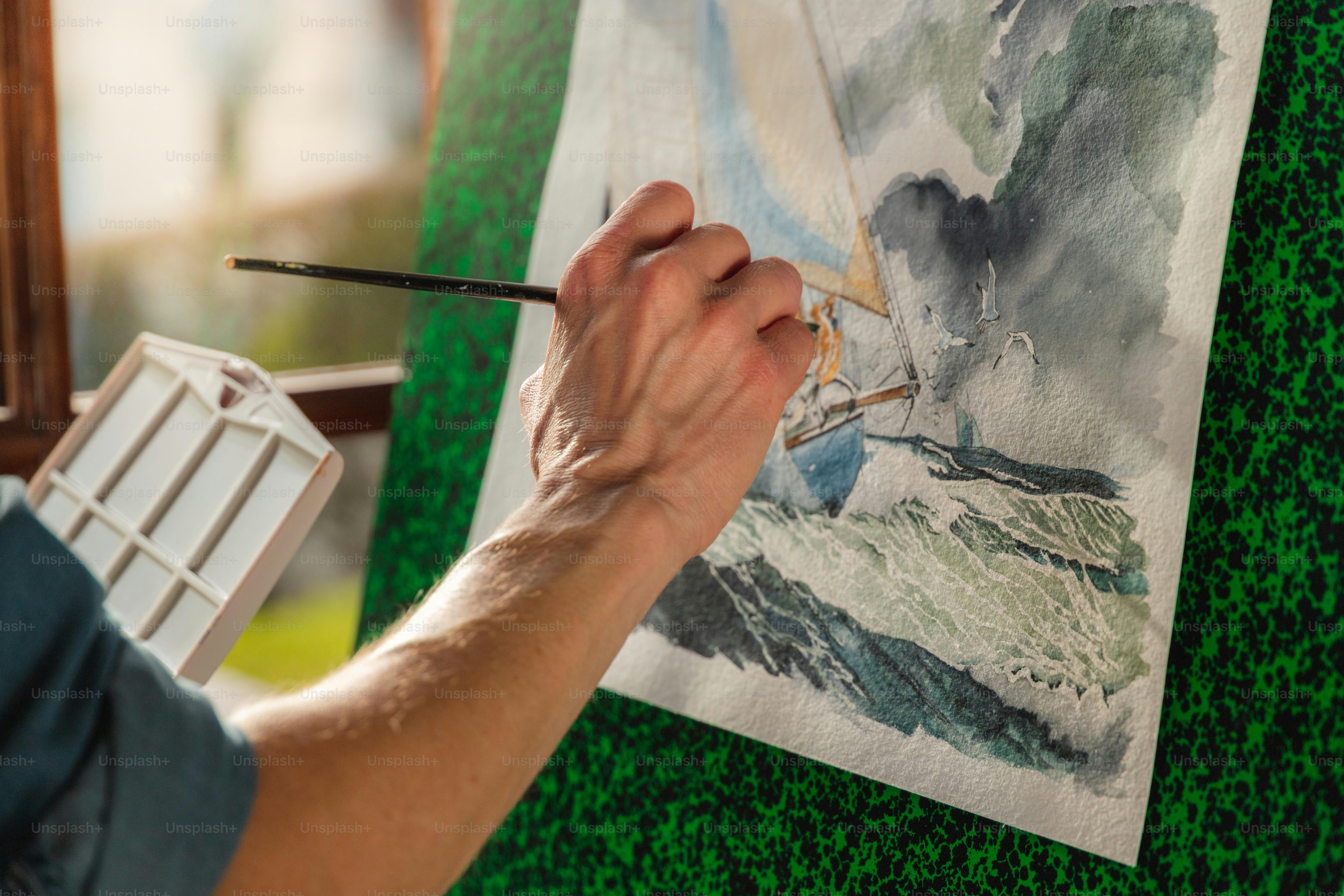 A man is painting a picture with a brush photo – Watercolor painting ...
