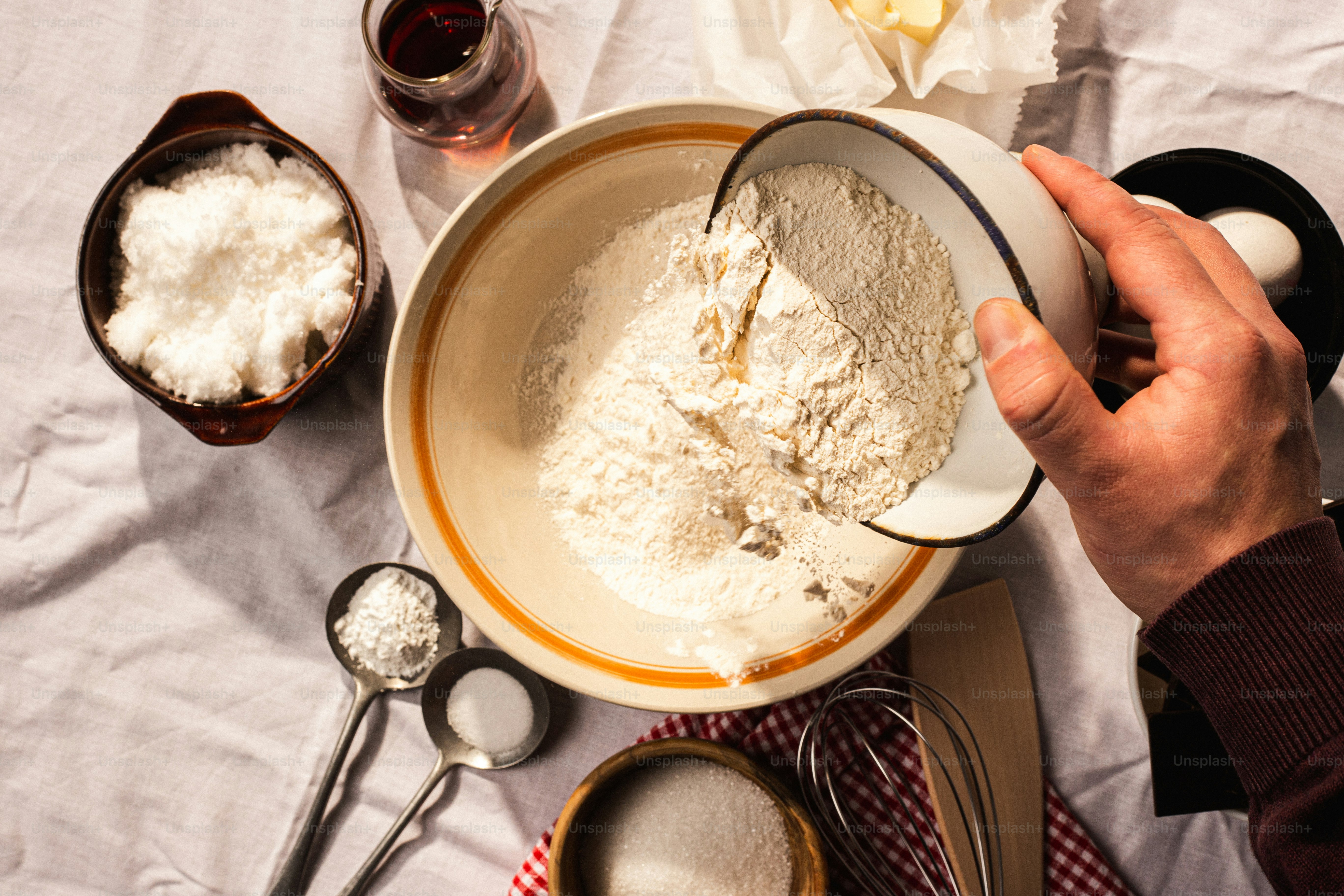 A person mixing ingredients in a bowl on a table photo – Baking Image ...