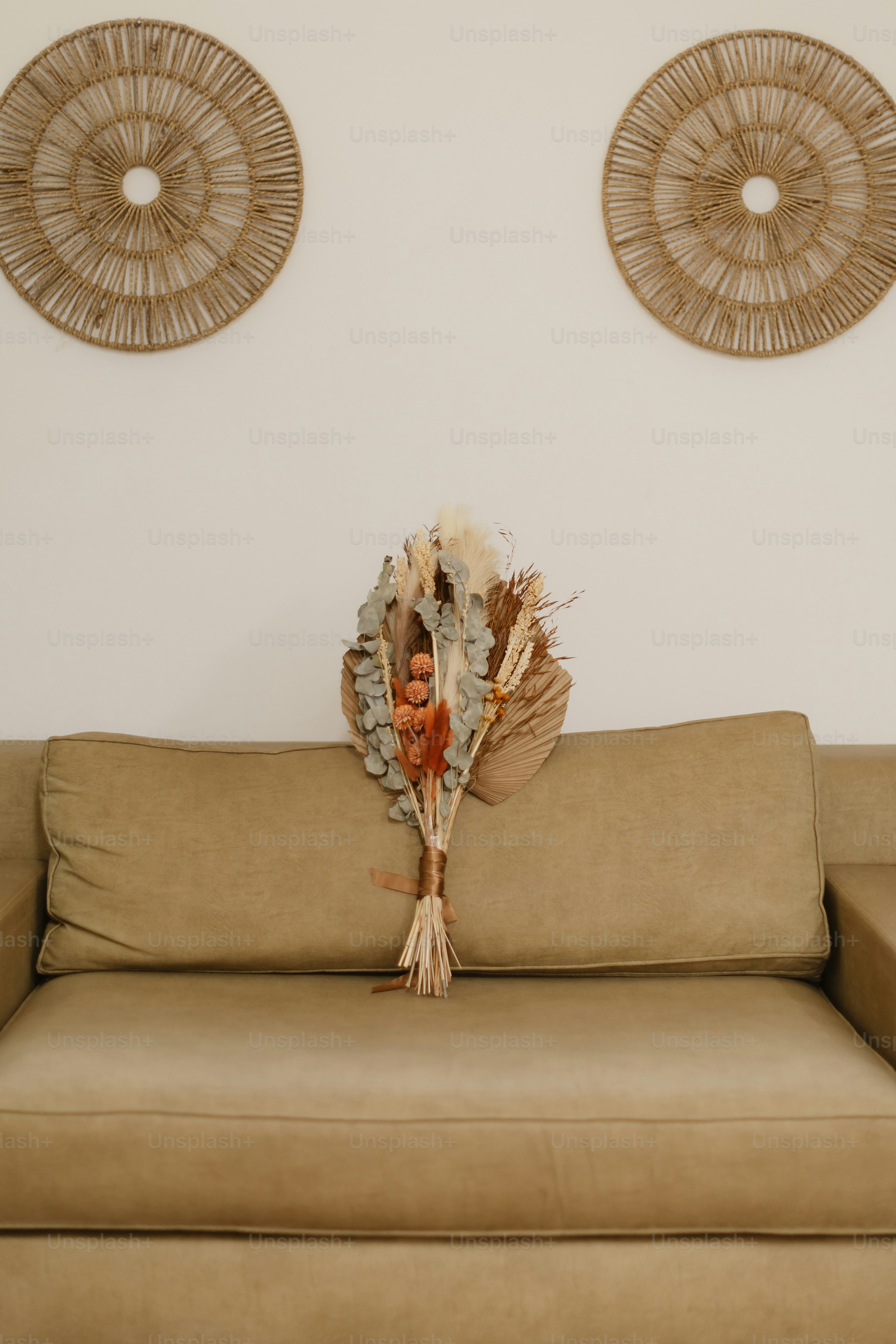 A couch with a bouquet of dried flowers on top of it photo – Art wall ...