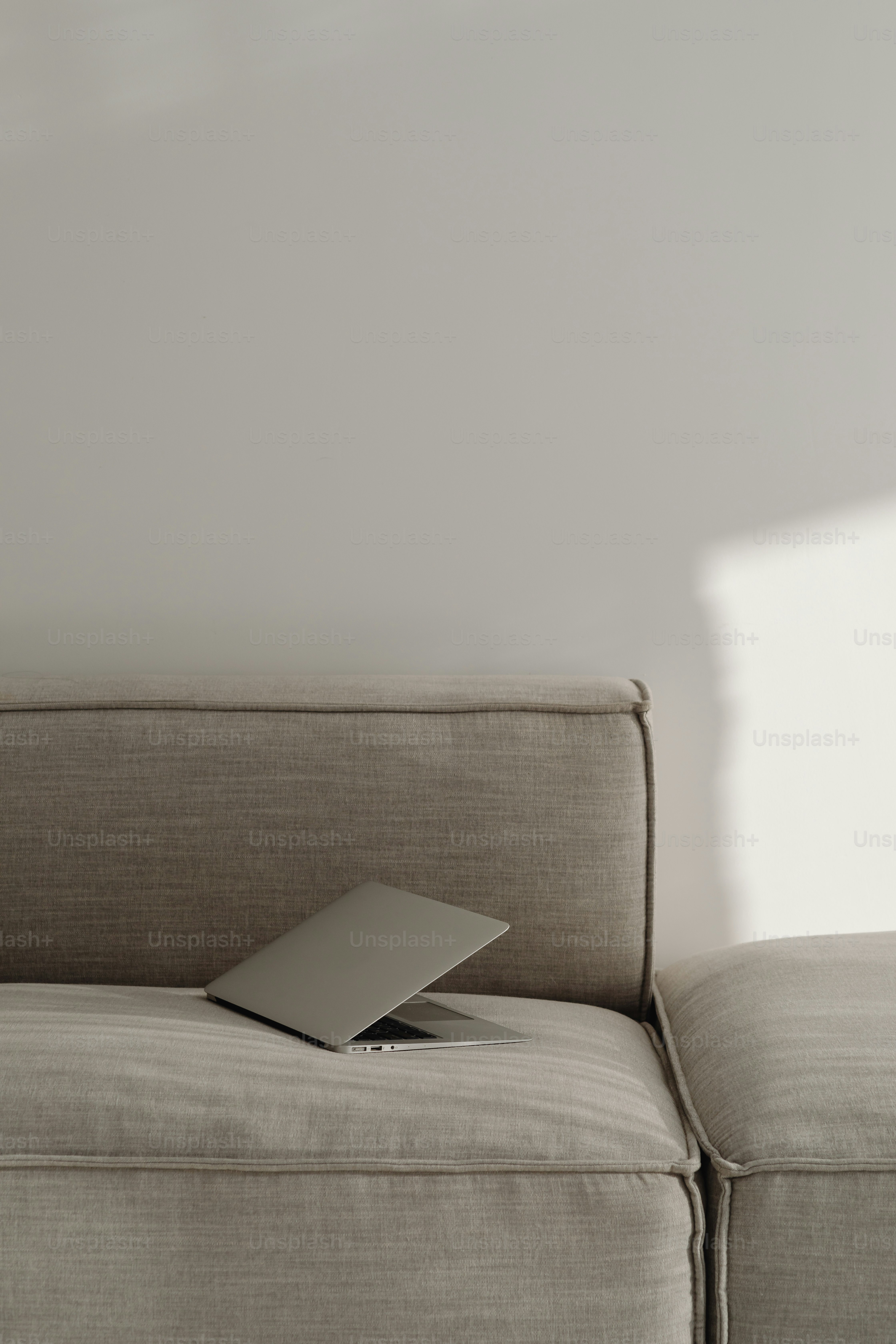 A laptop computer sitting on top of a couch photo – White interior ...