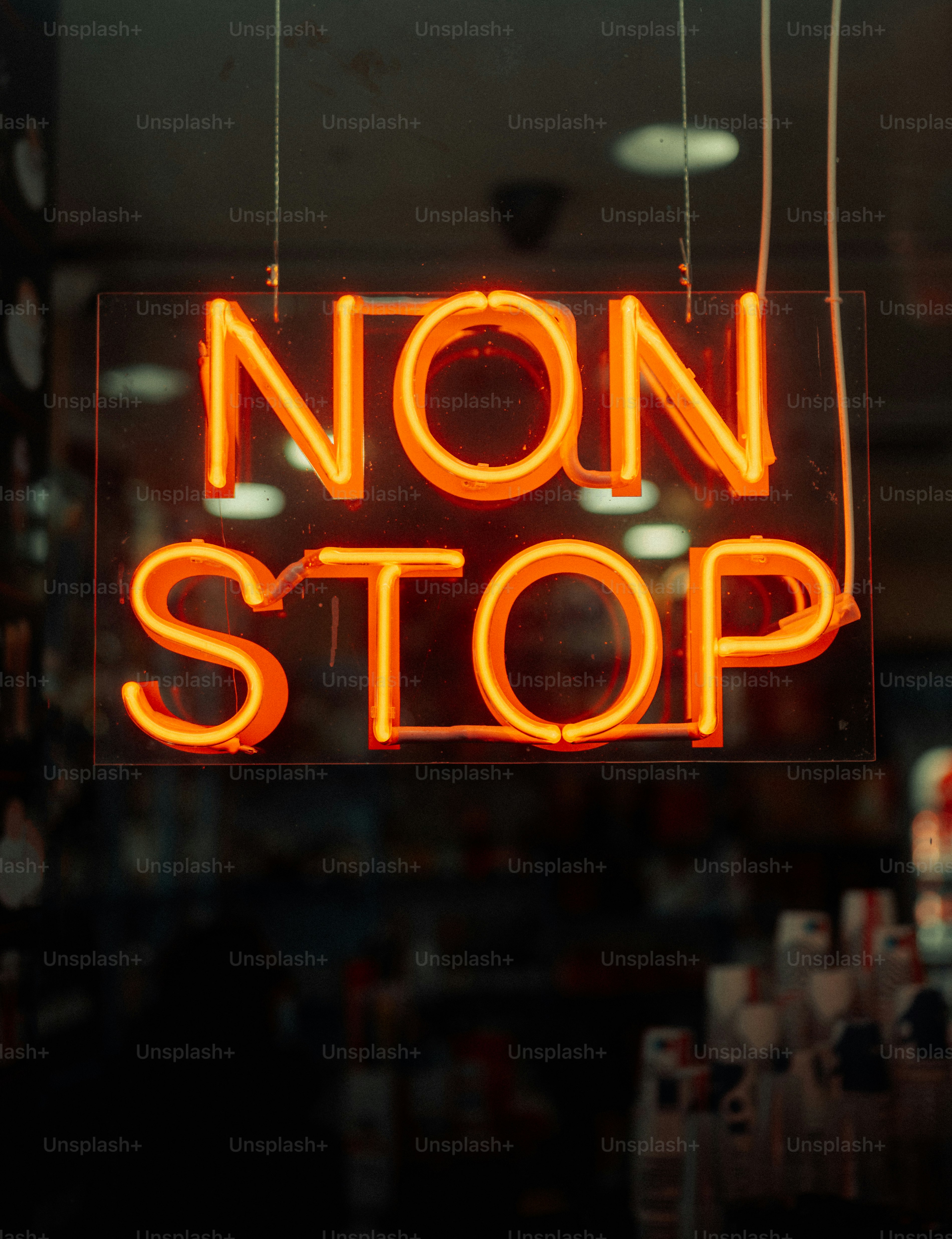 A neon sign that says non stop hanging from a window photo – Sign Image ...