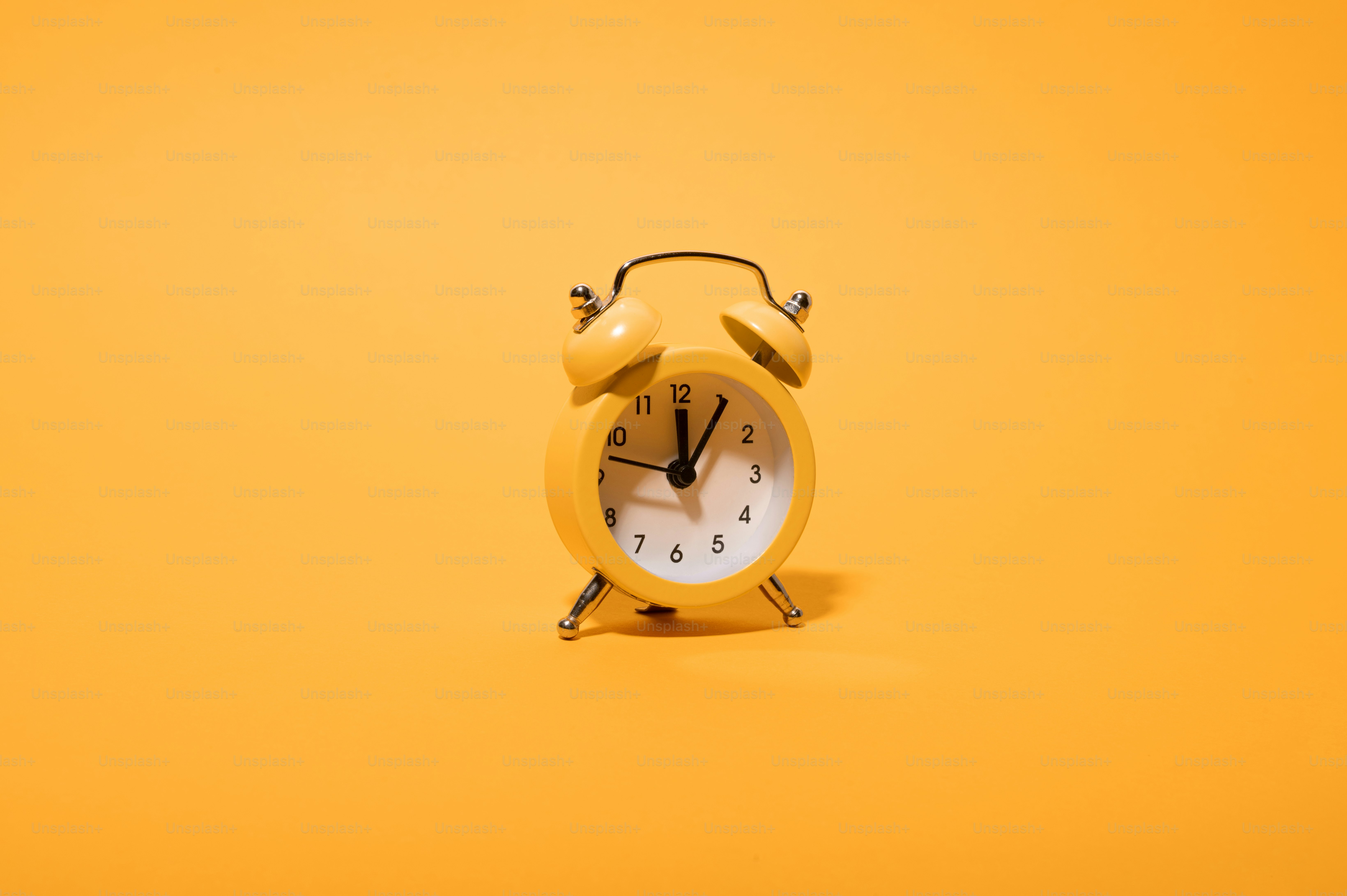 A yellow alarm clock on a yellow background photo – Old clock Image on ...