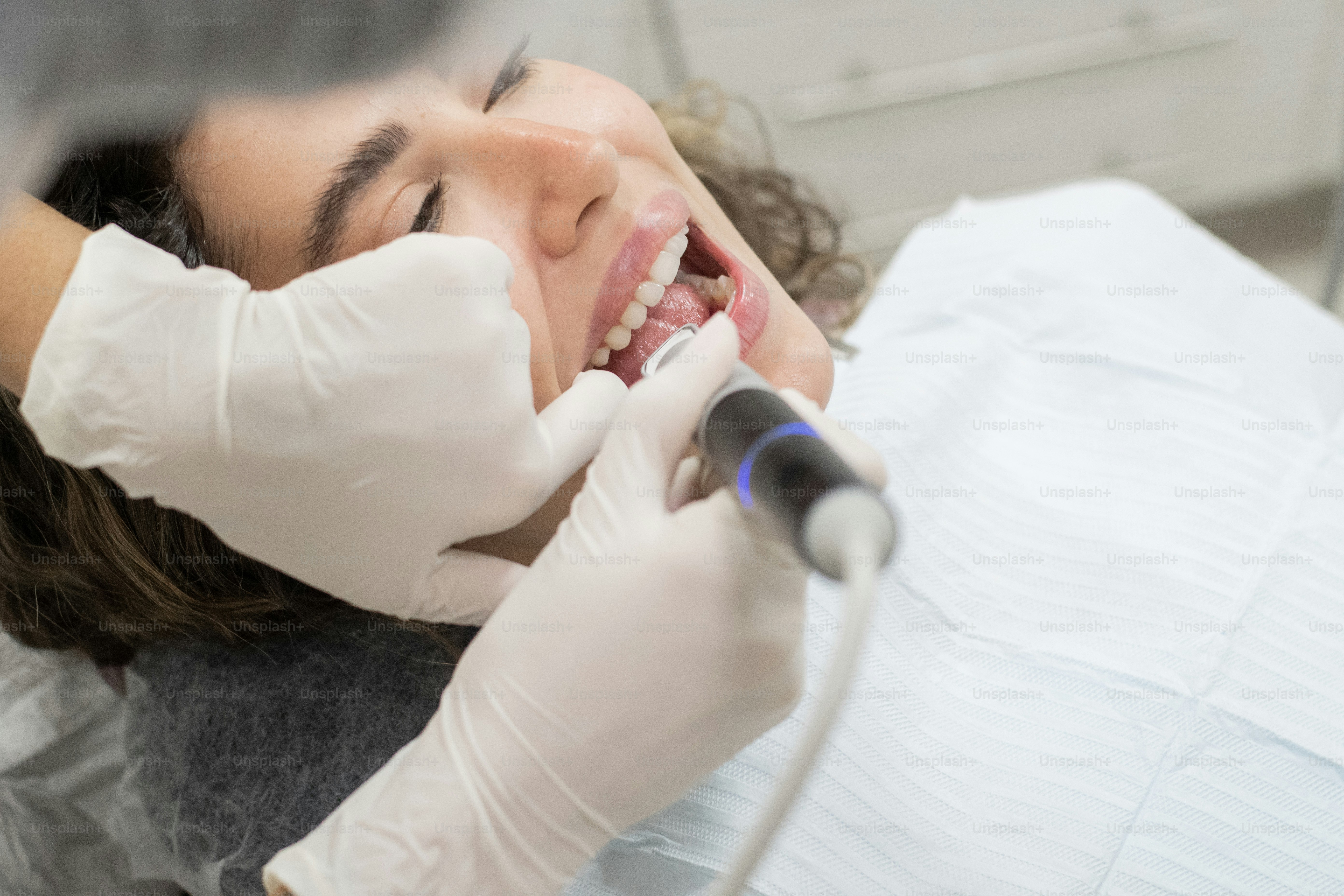 A woman getting her teeth checked by a dentist photo – White teeth ...