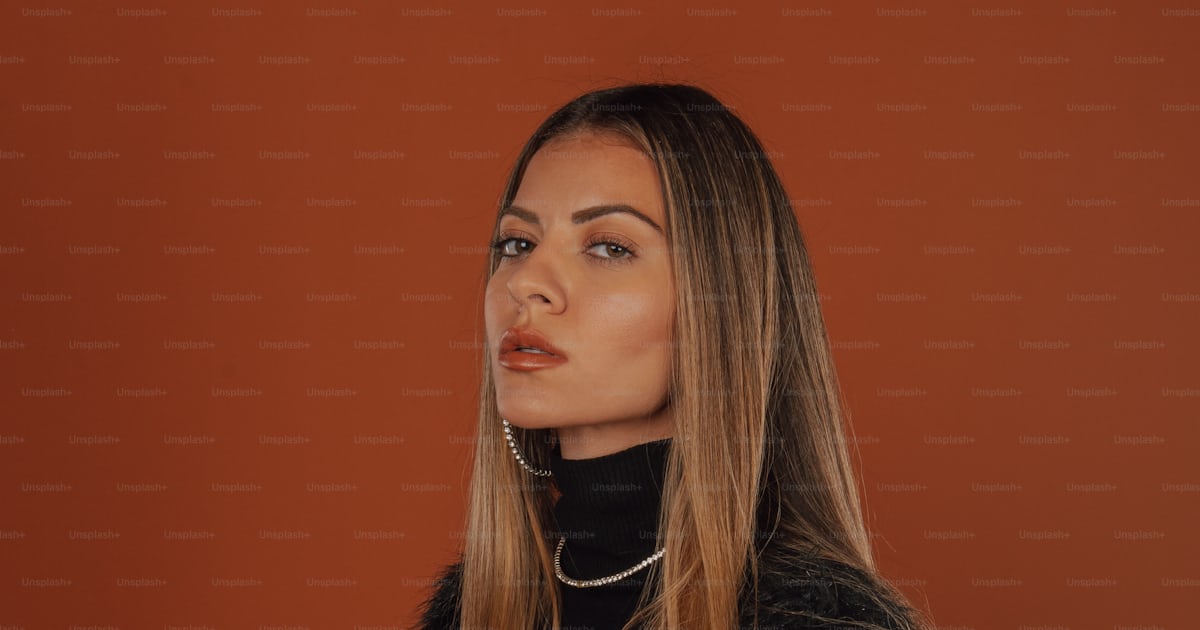 Foto Una Mujer Parada Frente A Una Pared Roja Retrato Imagen En Unsplash