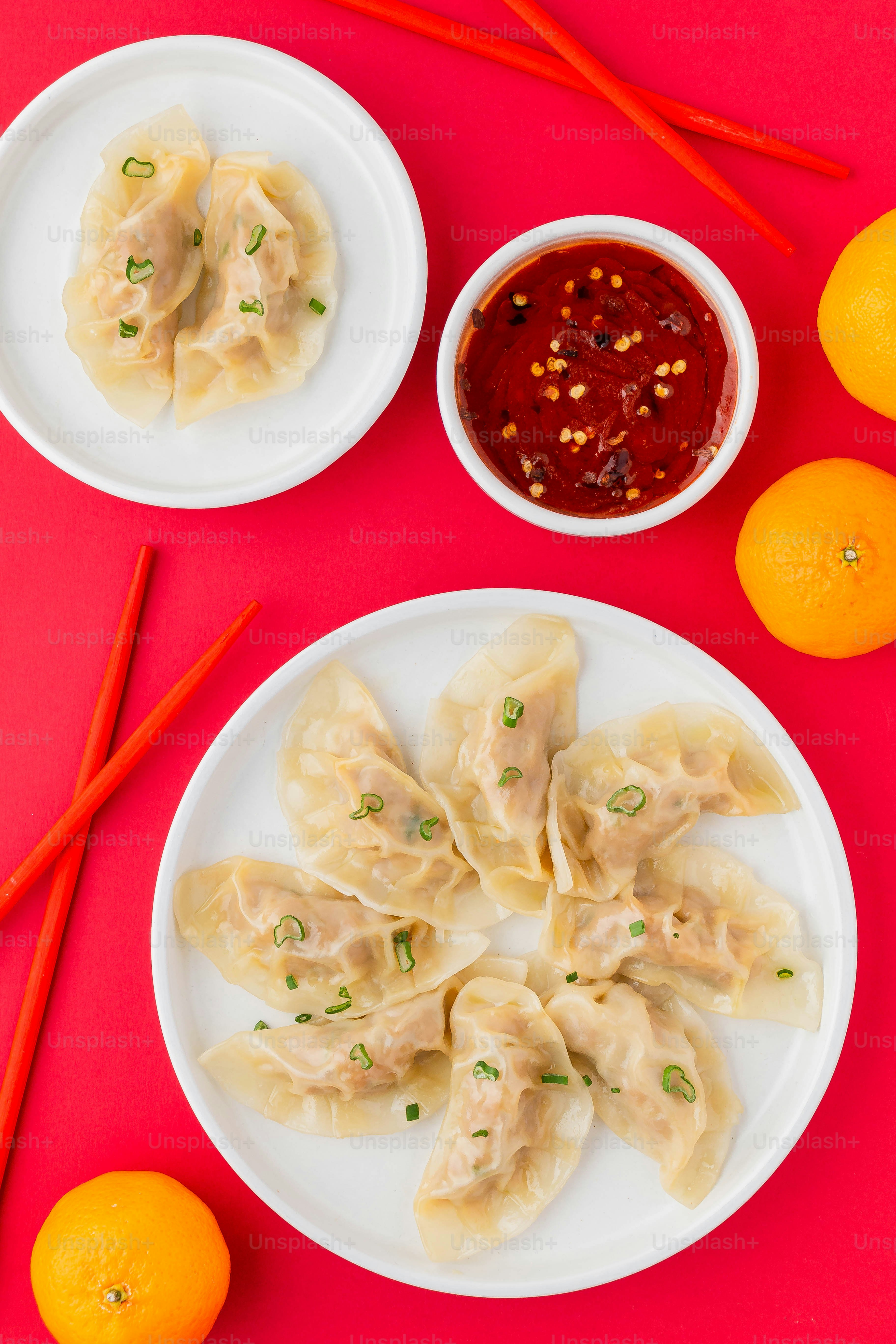 A plate of dumplings with dipping sauce next to oranges photo – Chinese ...