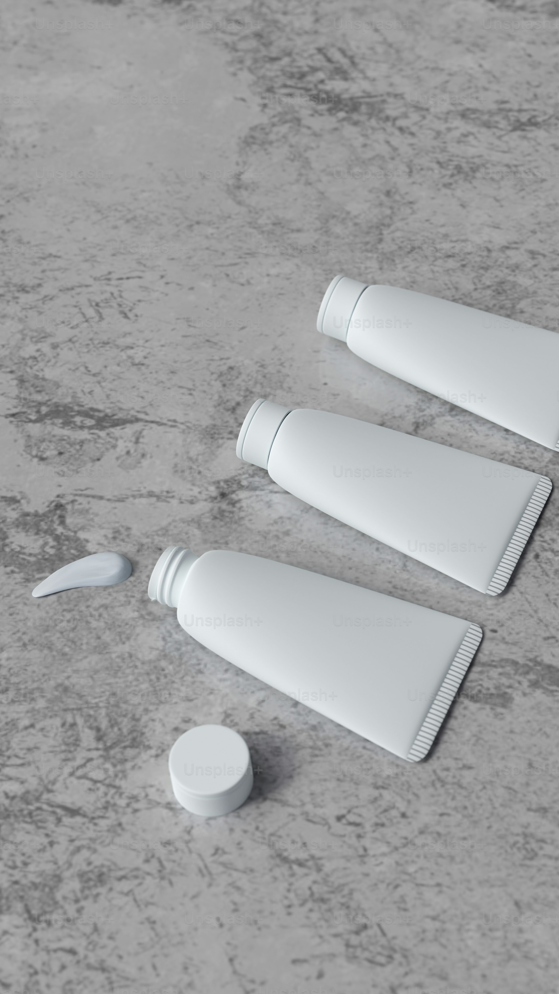 Three white toothbrushes and a tube of toothpaste on a gray surface ...