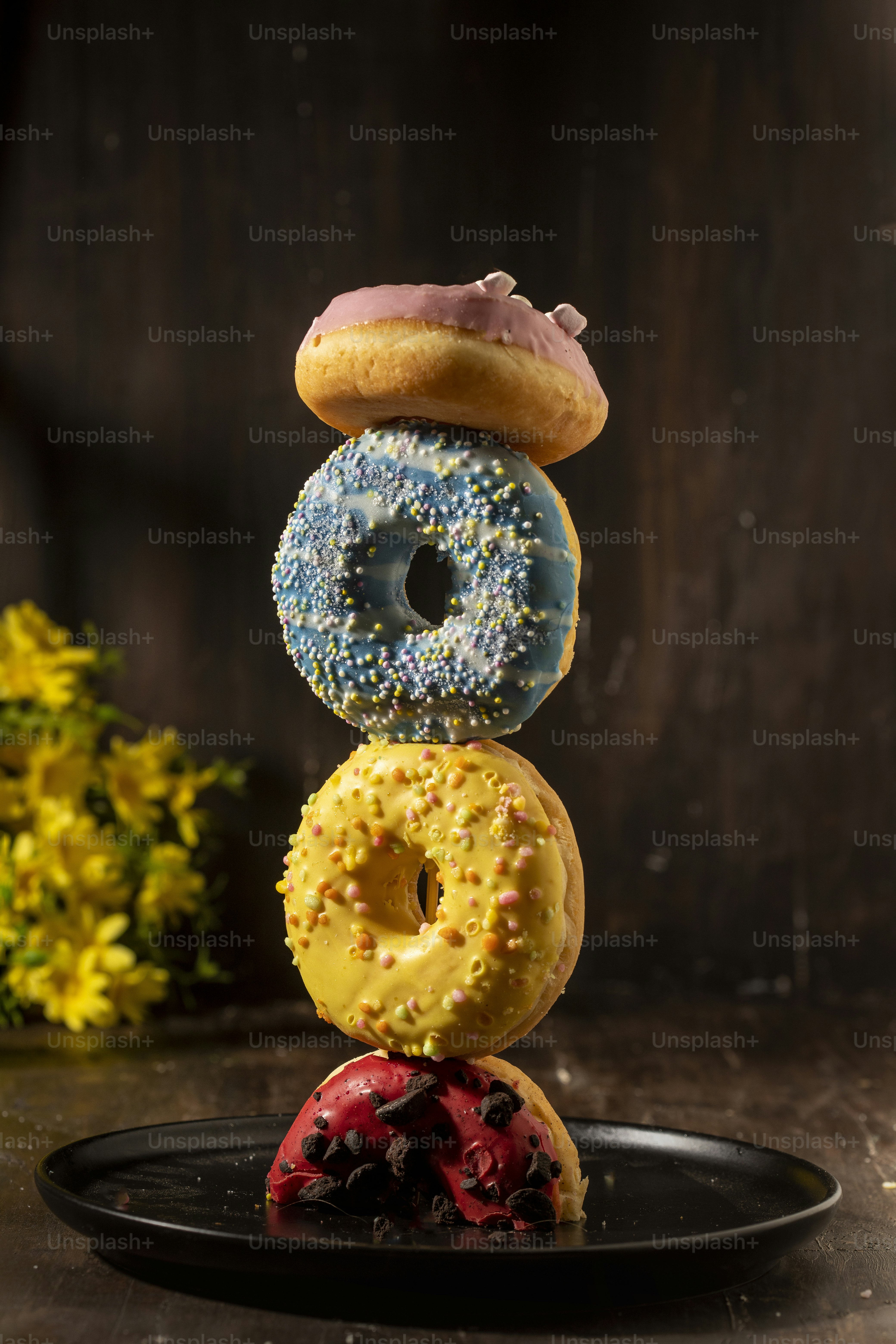 A stack of donuts sitting on top of a black plate photo – Sweet treats ...