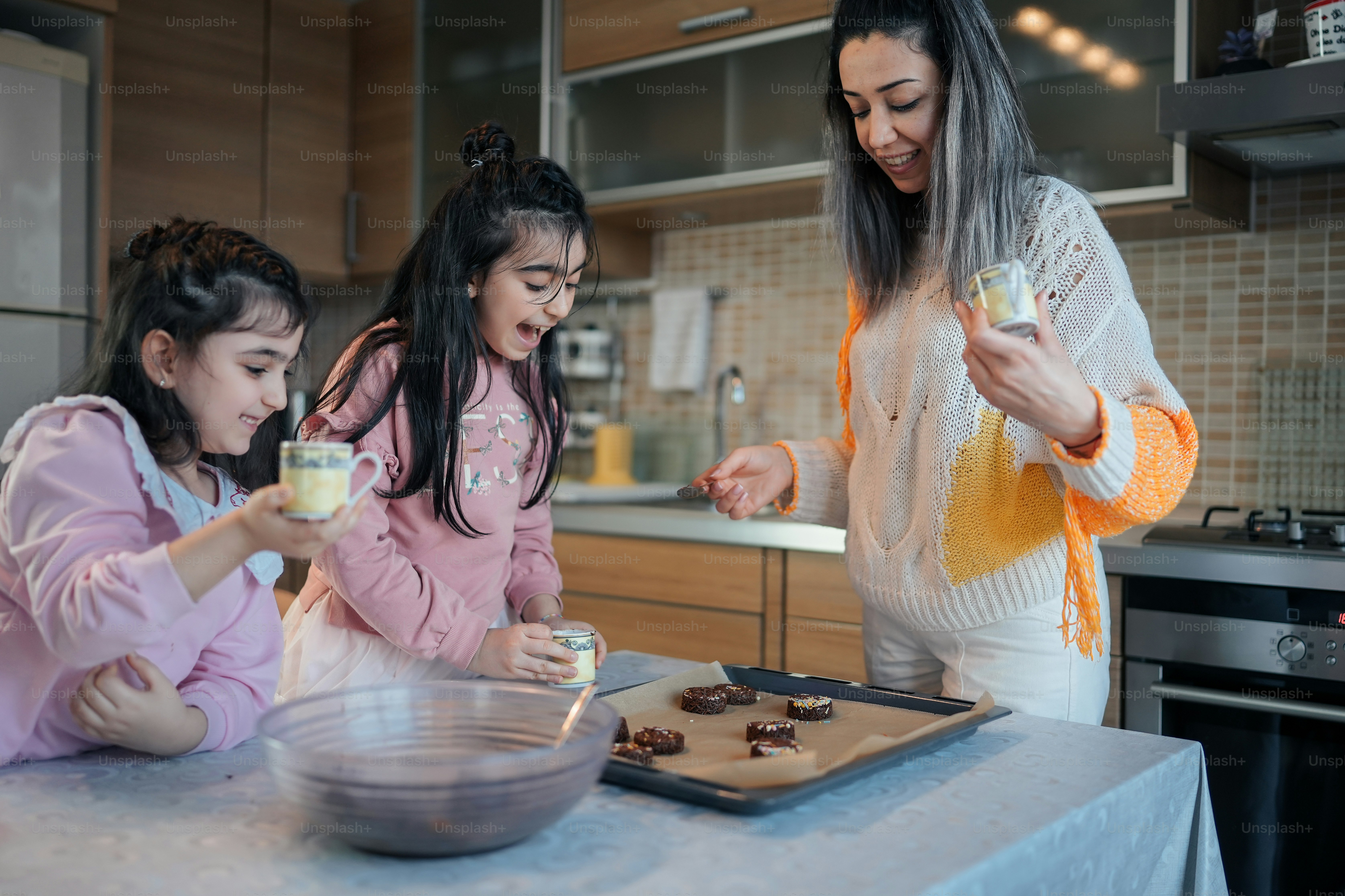 A group of young girls standing around a kitchen counter photo – Person ...