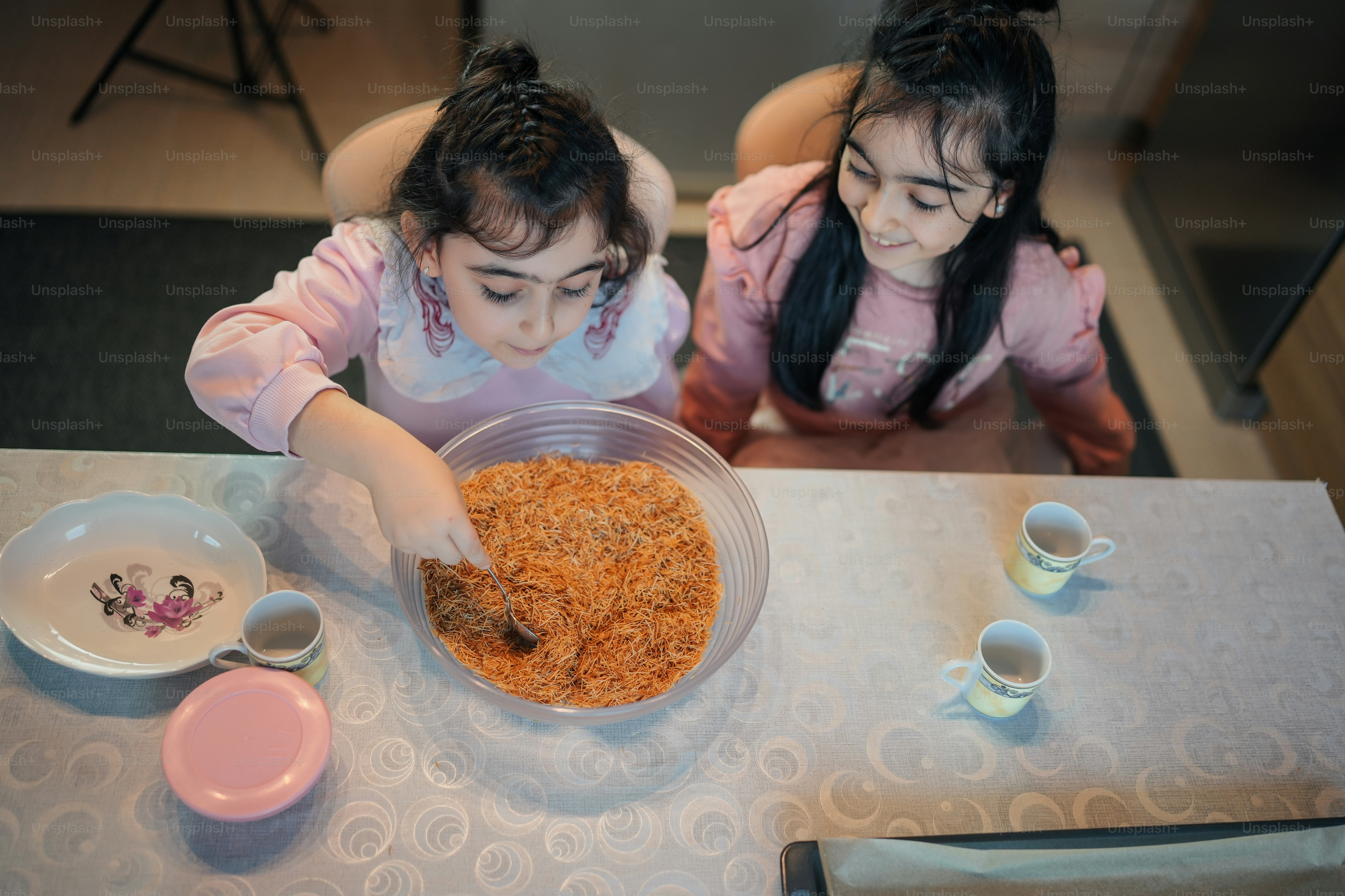 Two young girls sitting at a table making food photo – Cooking Image on ...