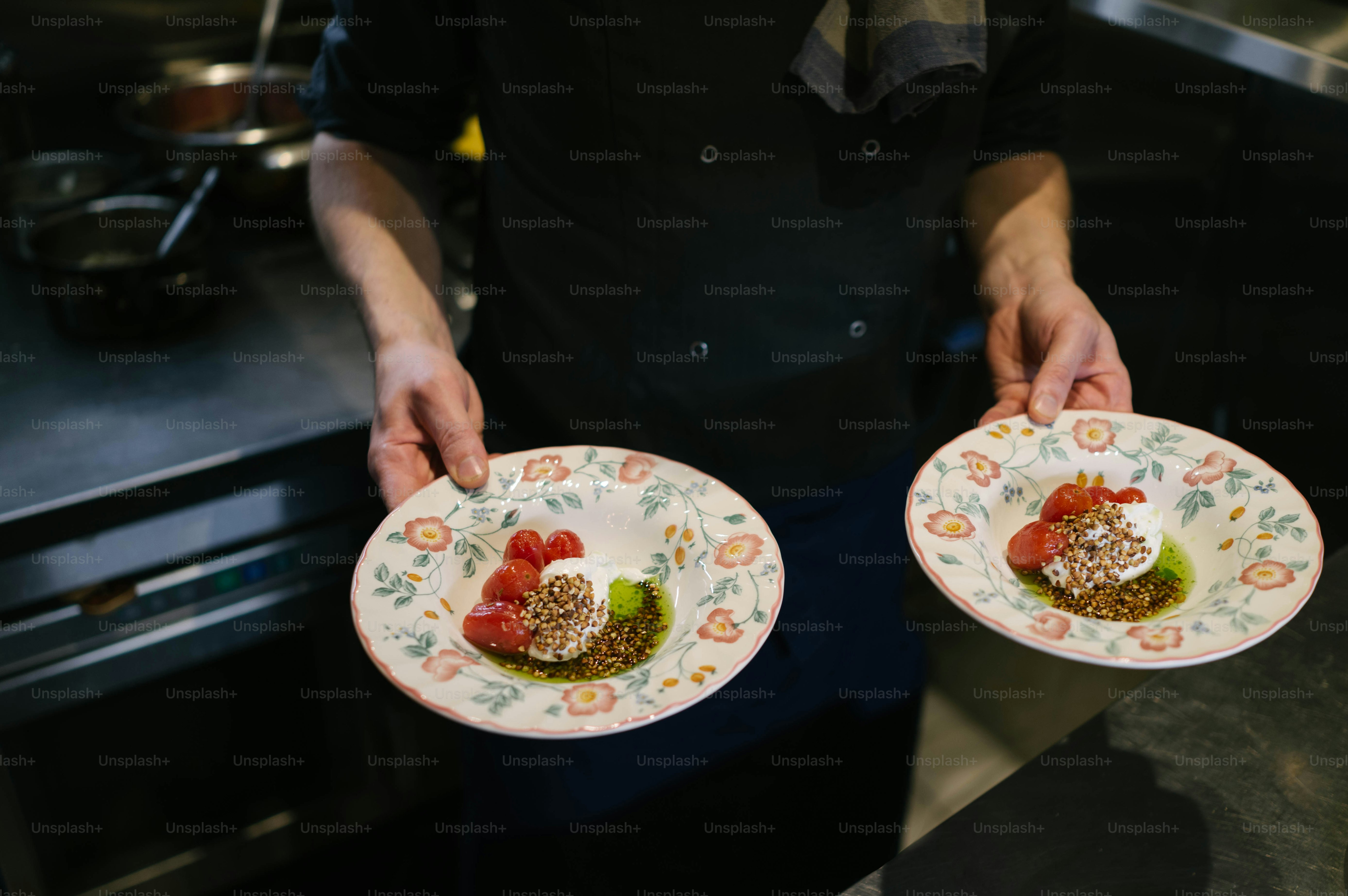 A person holding two plates with food on them photo – Plating Image on ...