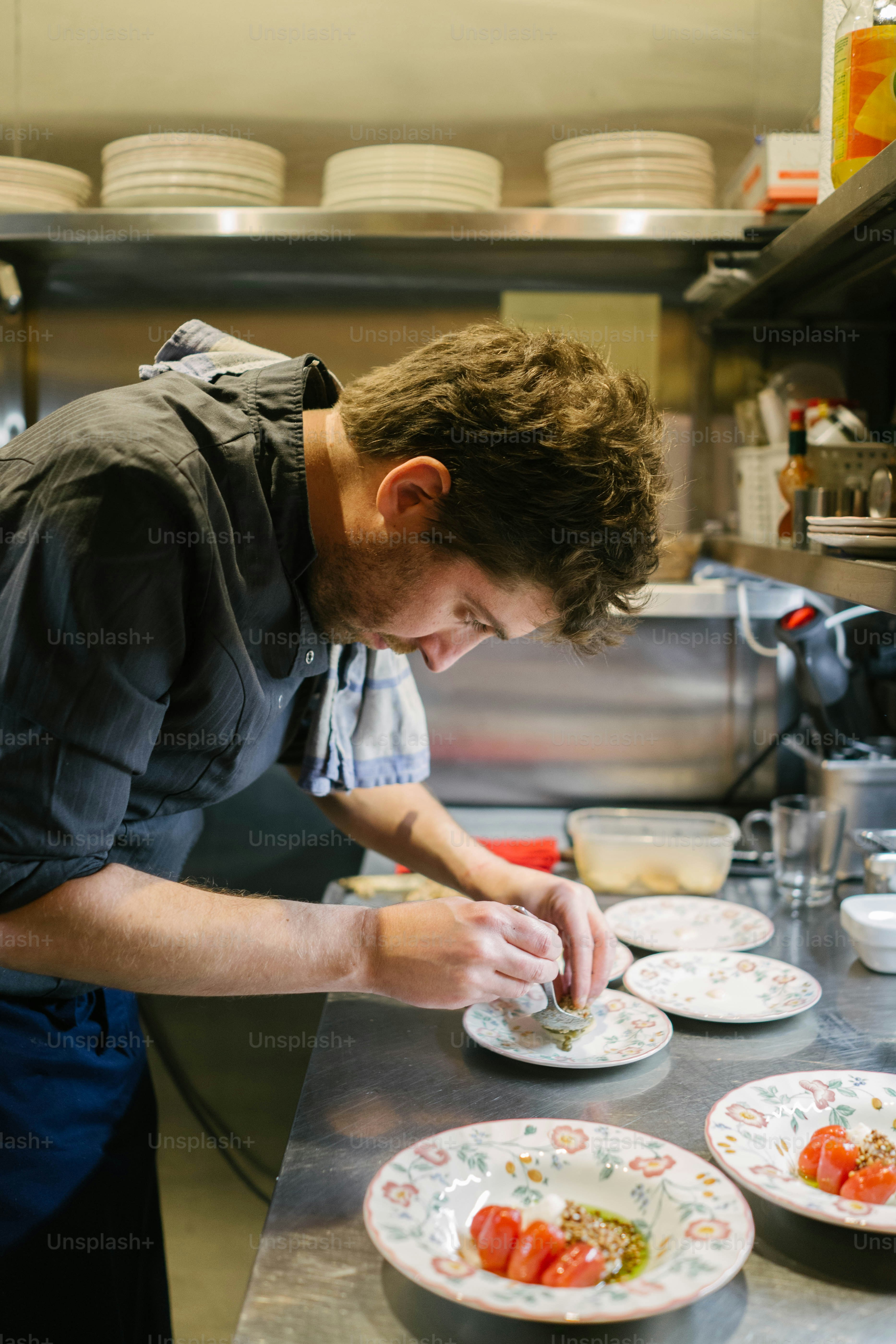 A person in a kitchen preparing food on a plate photo – Fine dining ...
