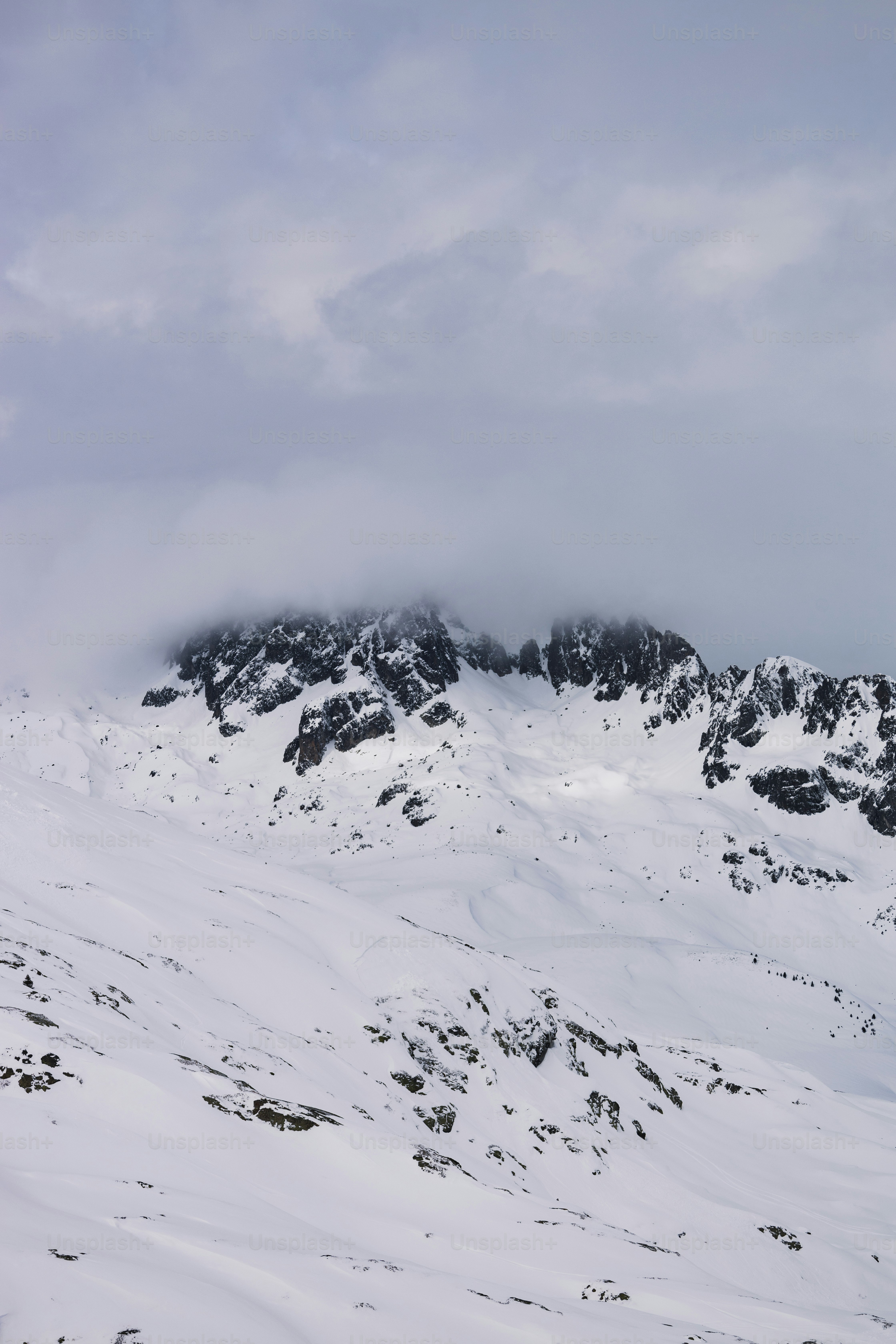 A mountain covered in snow and clouds under a cloudy sky photo – Snow ...
