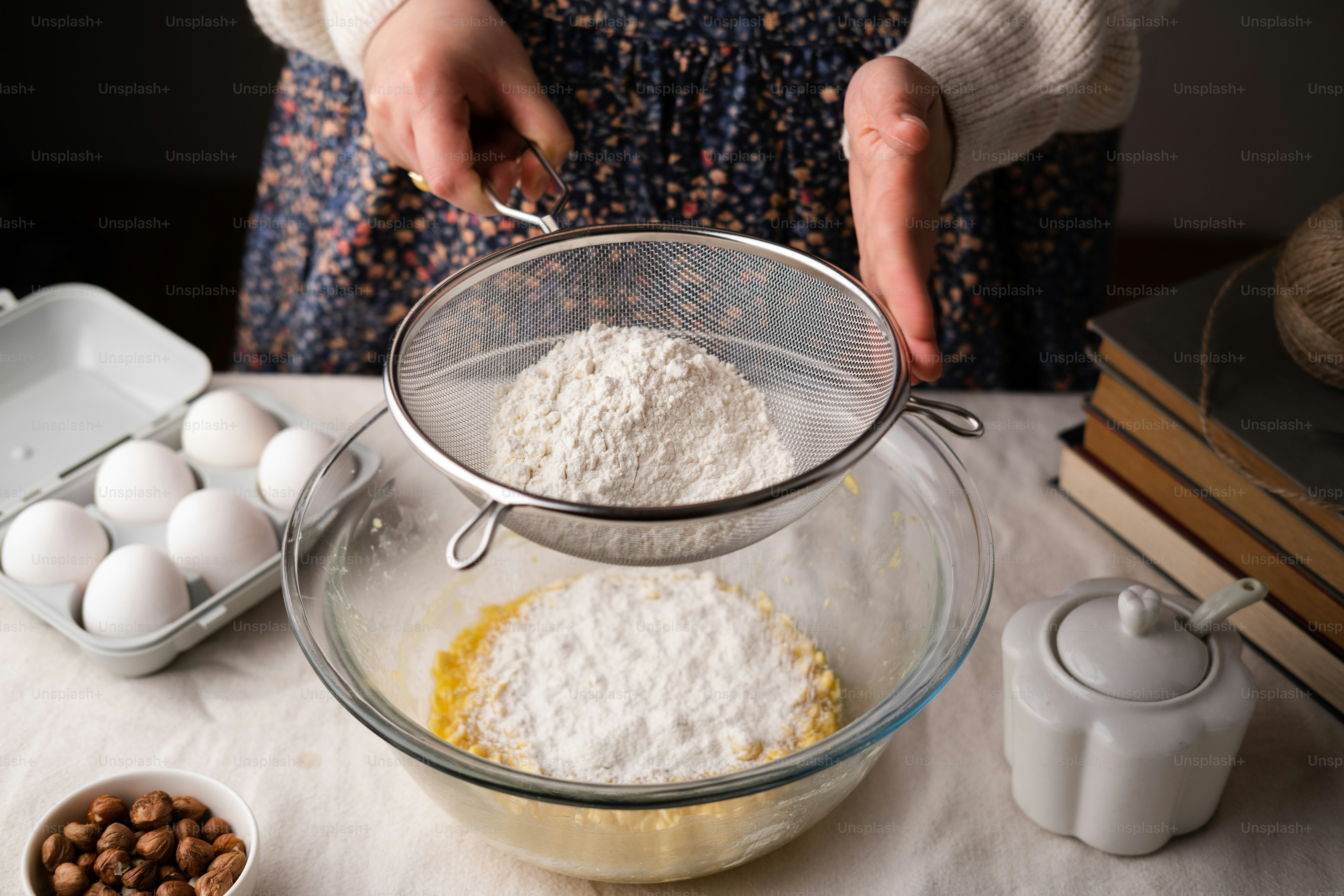 A person mixing ingredients in a bowl on a table photo – Flour Image on ...