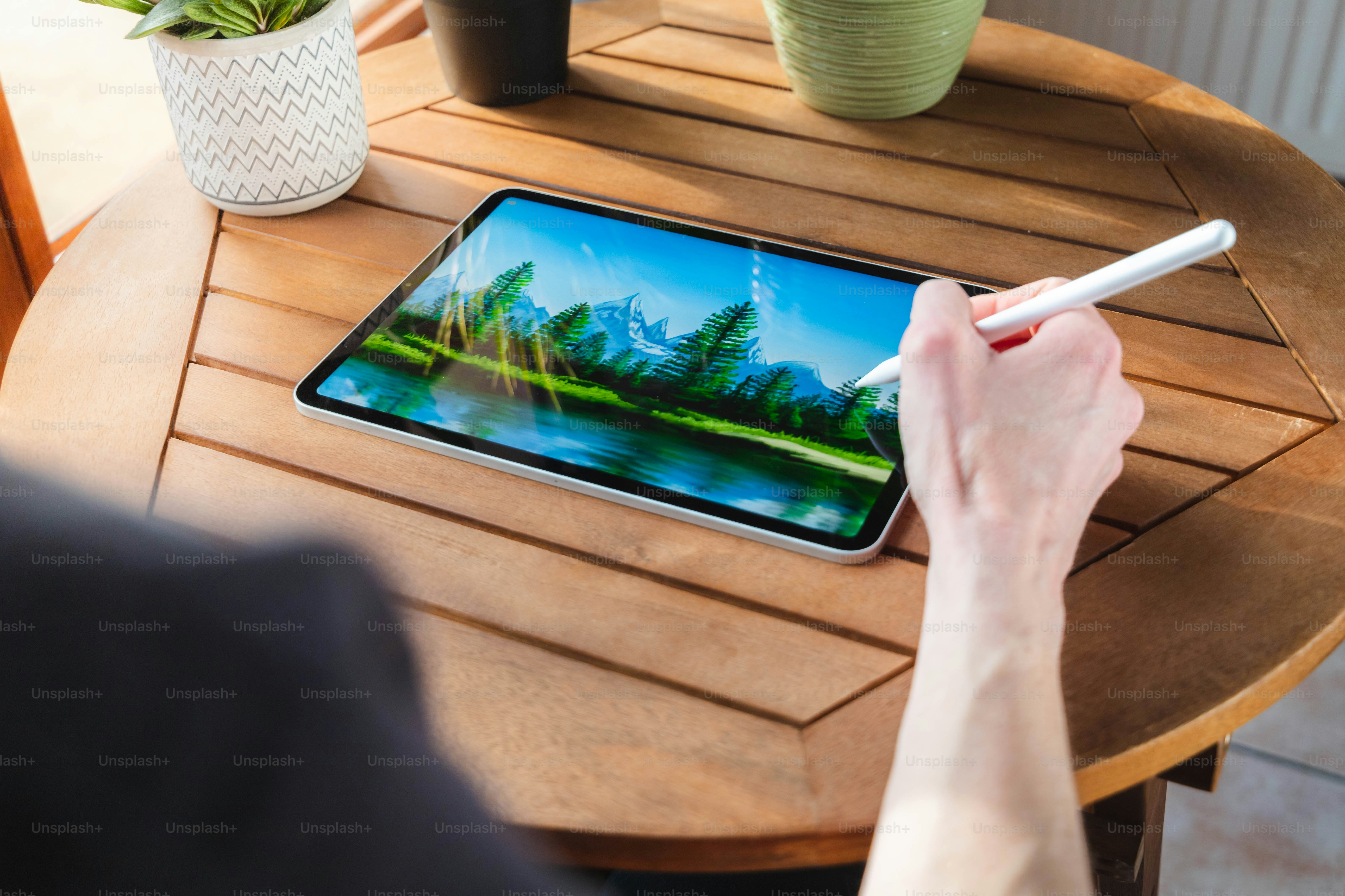 Foto zum Thema Eine Person, die mit einem Tablet an einem Tisch sitzt ...