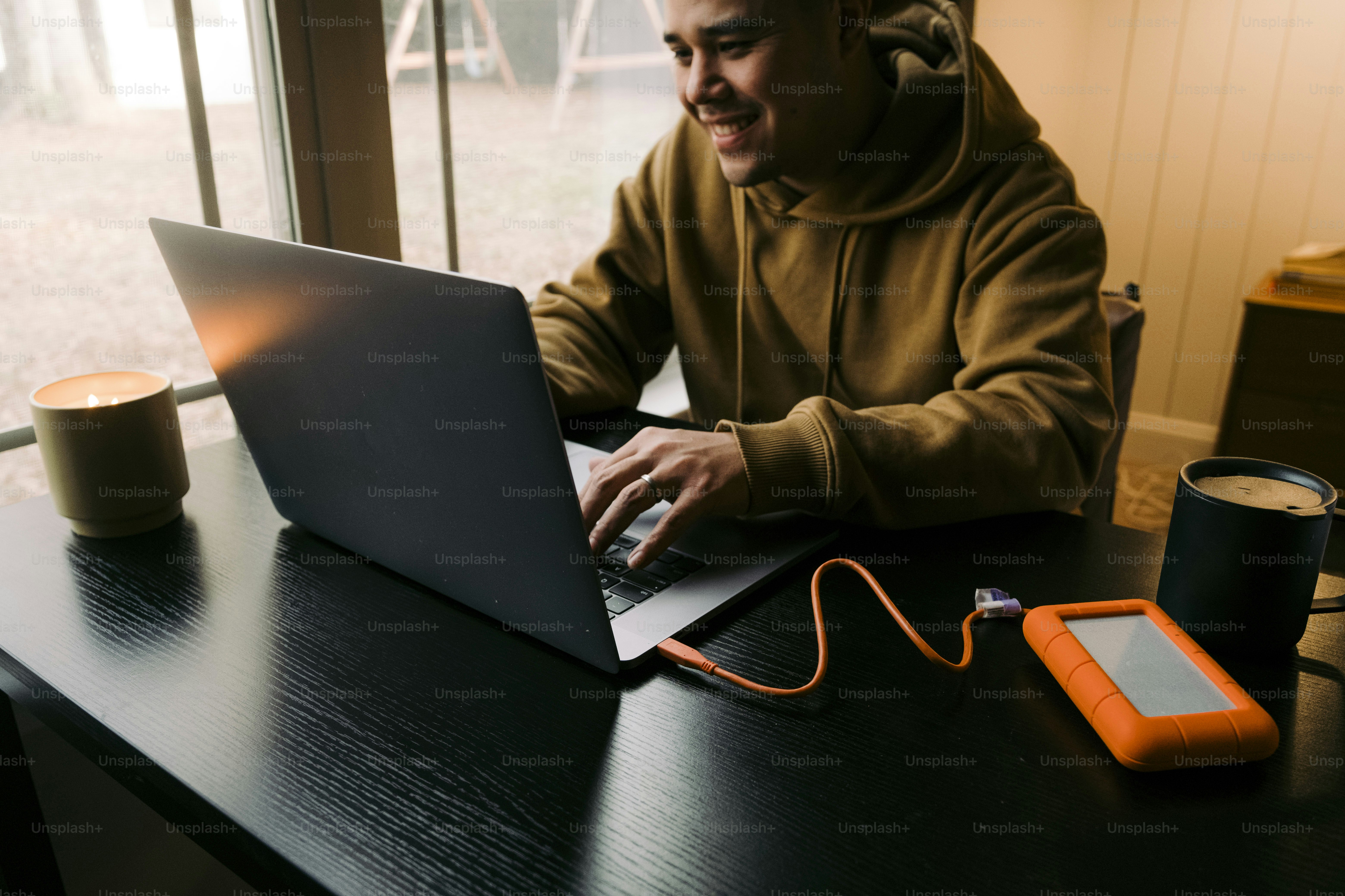 A man sitting at a table using a laptop computer photo – Lider Image on ...