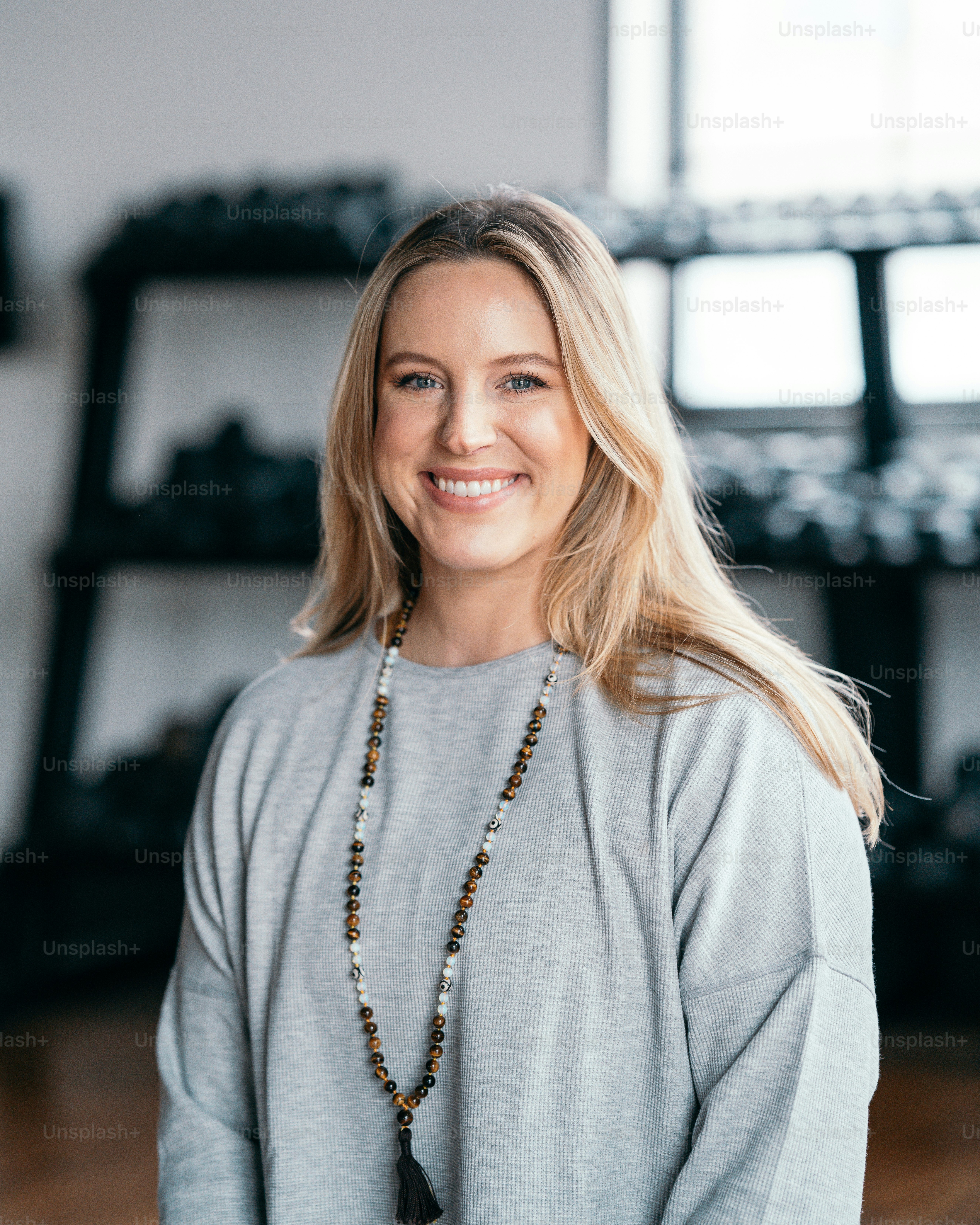 A woman standing in a room with a necklace on her neck photo – Woman ...