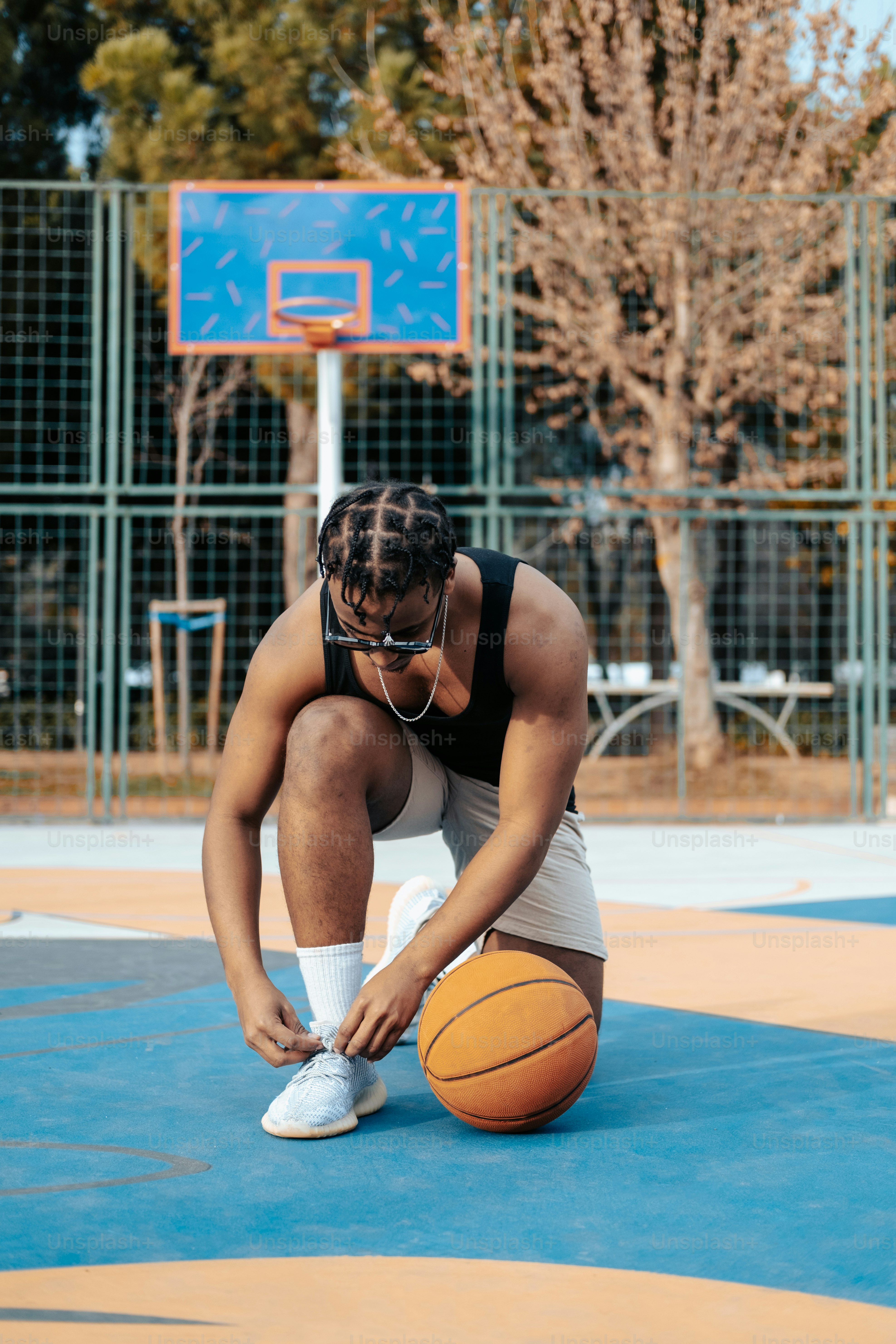 Foto zum Thema Ein Mann, der auf einem Basketballplatz sitzt und einen ...