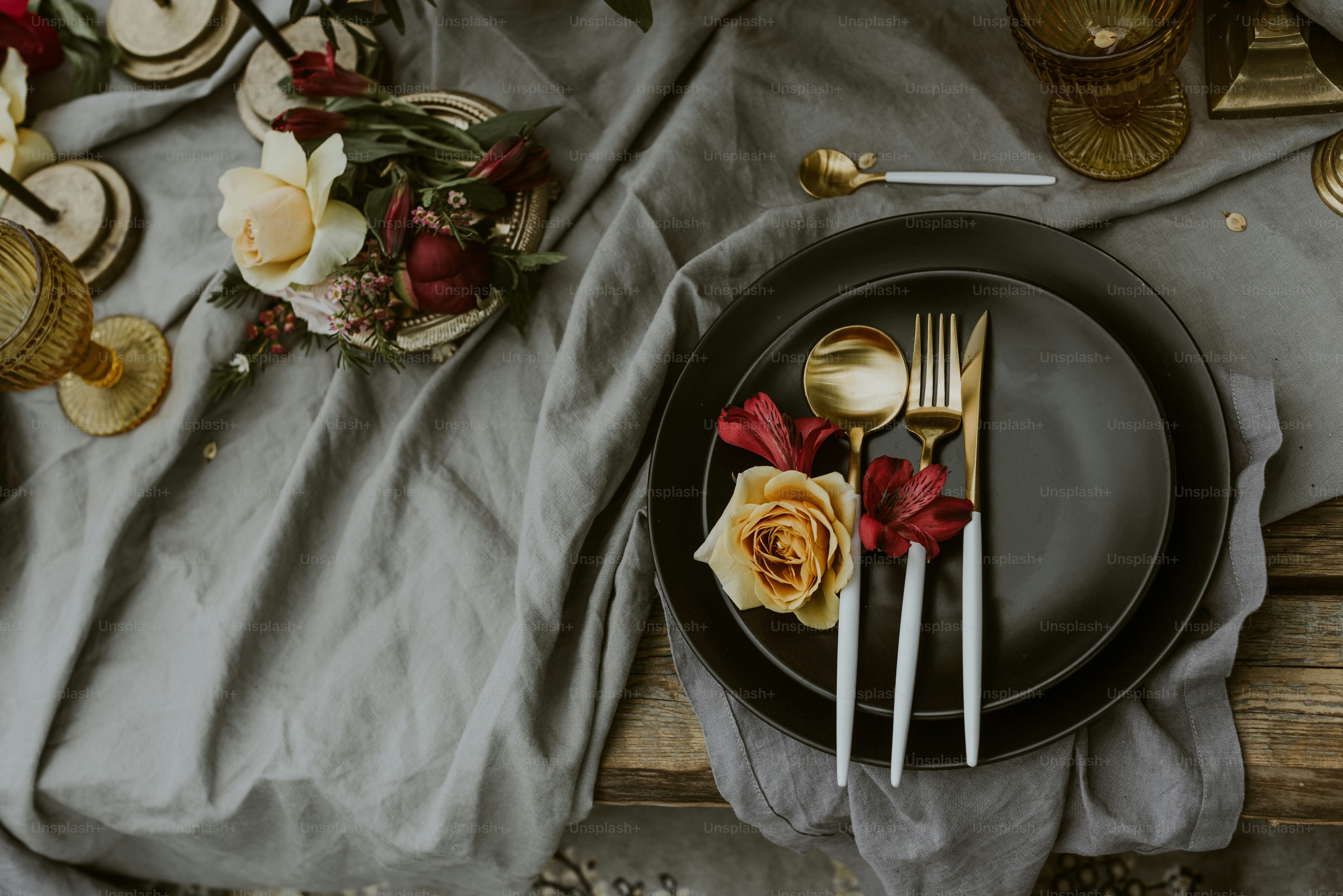 A black plate topped with flowers next to a fork and knife photo ...