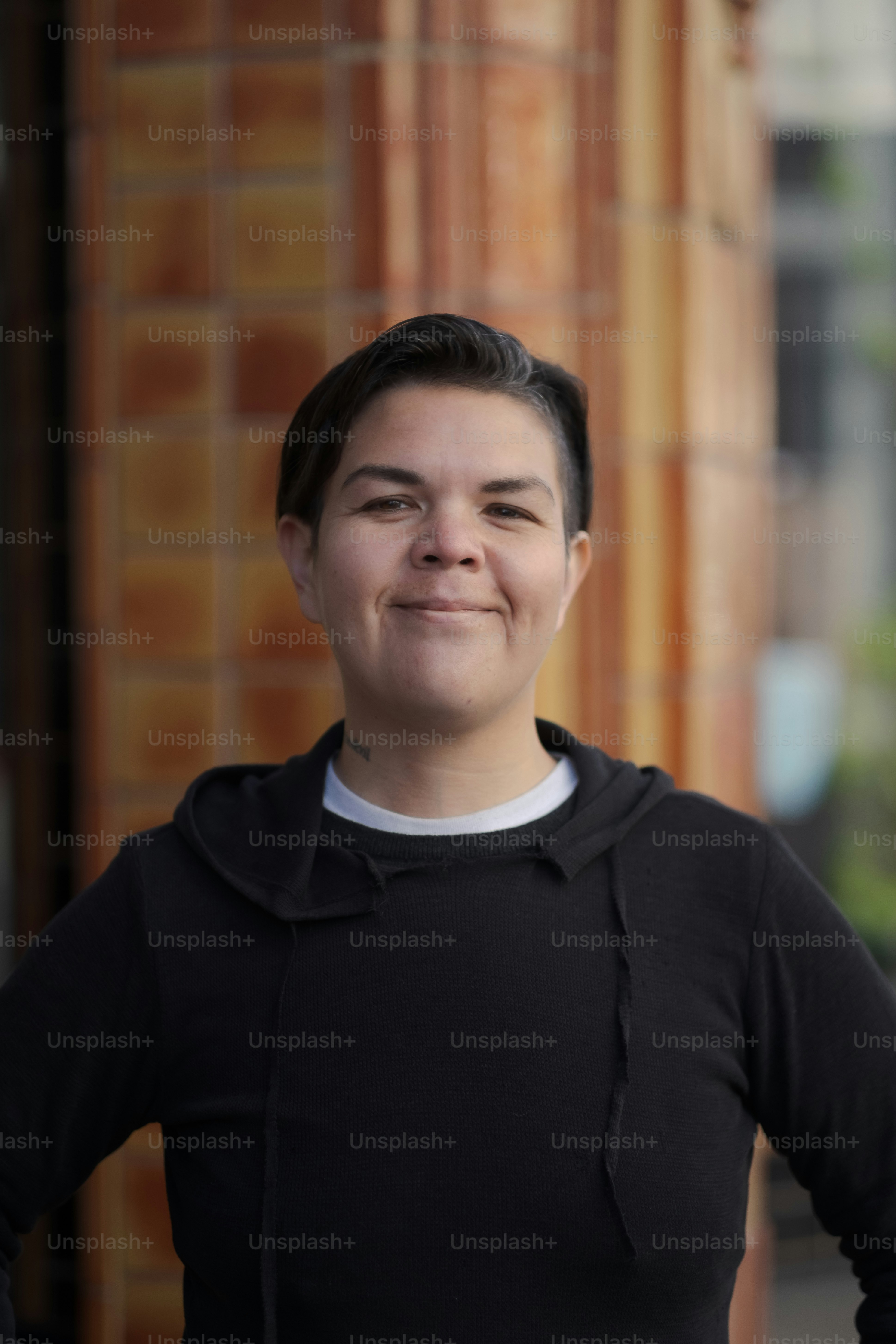 A woman standing in front of a brick building photo – Multiracial Image ...