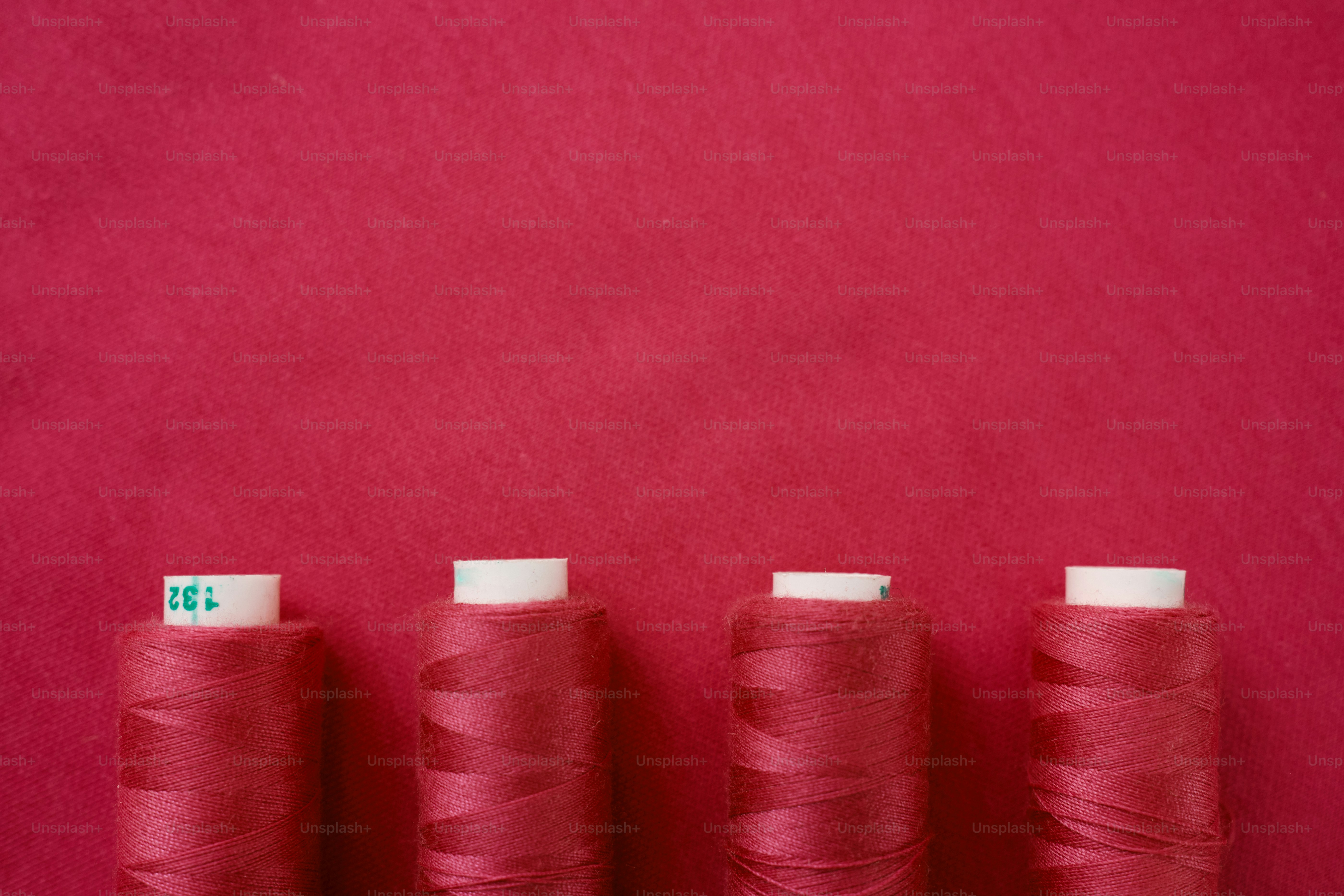 Three spools of red thread on a red background photo – Pantone 2022 ...