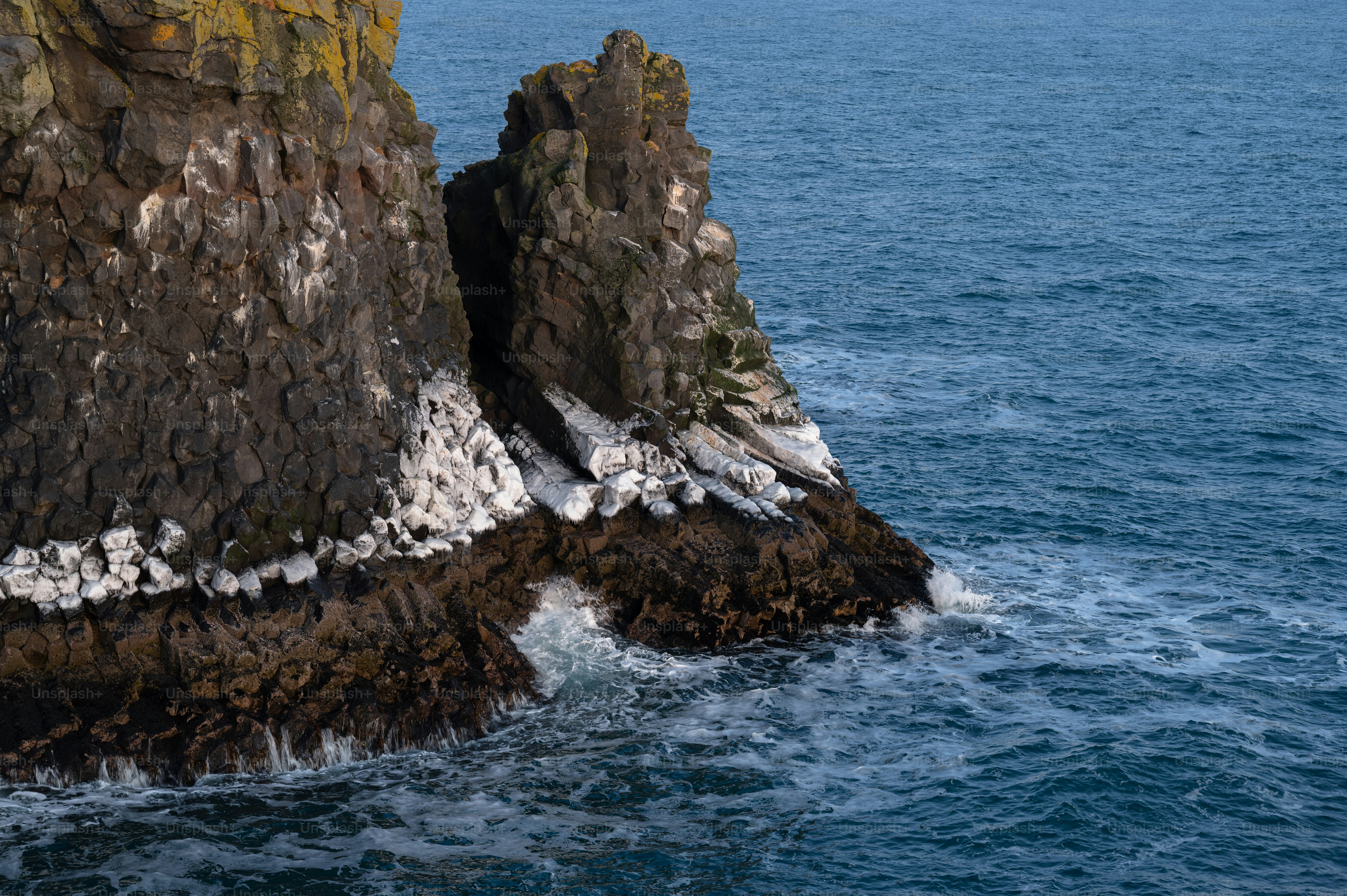 A rock outcropping in the middle of the ocean photo – Sea waves Image ...