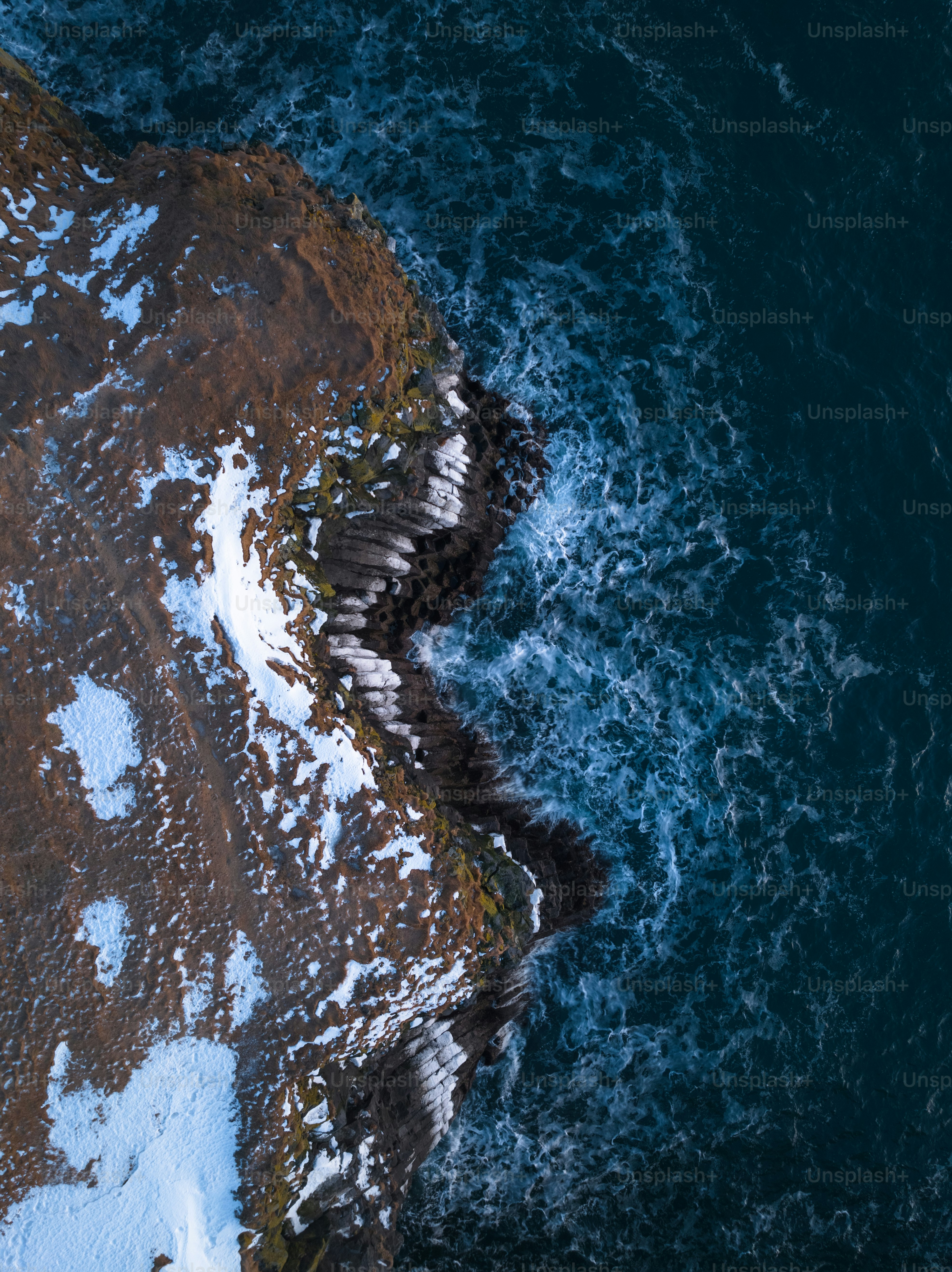 An aerial view of the ocean and land covered in snow photo – Ice Image ...