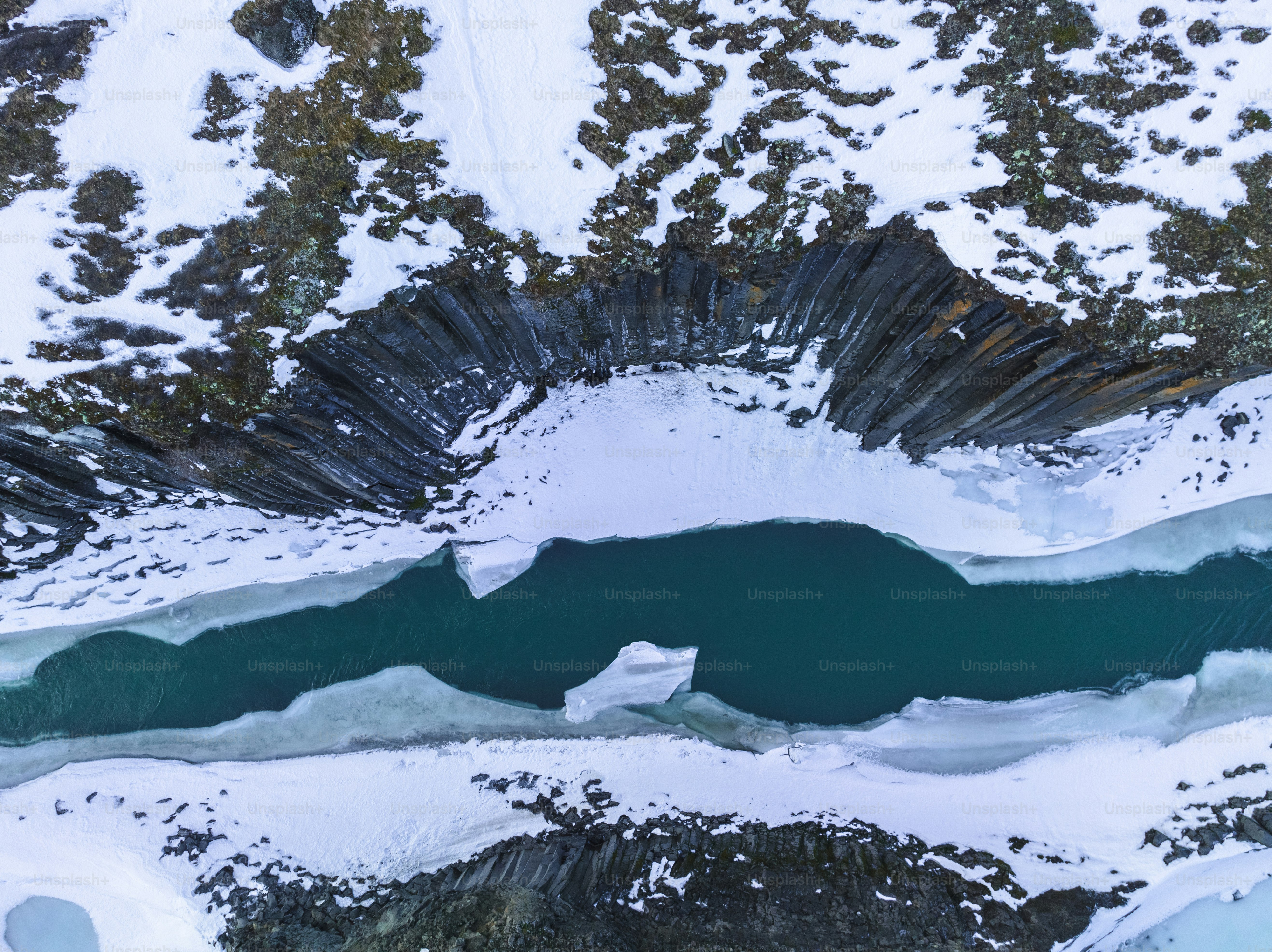 An aerial view of a lake surrounded by snow photo – Nature Image on ...