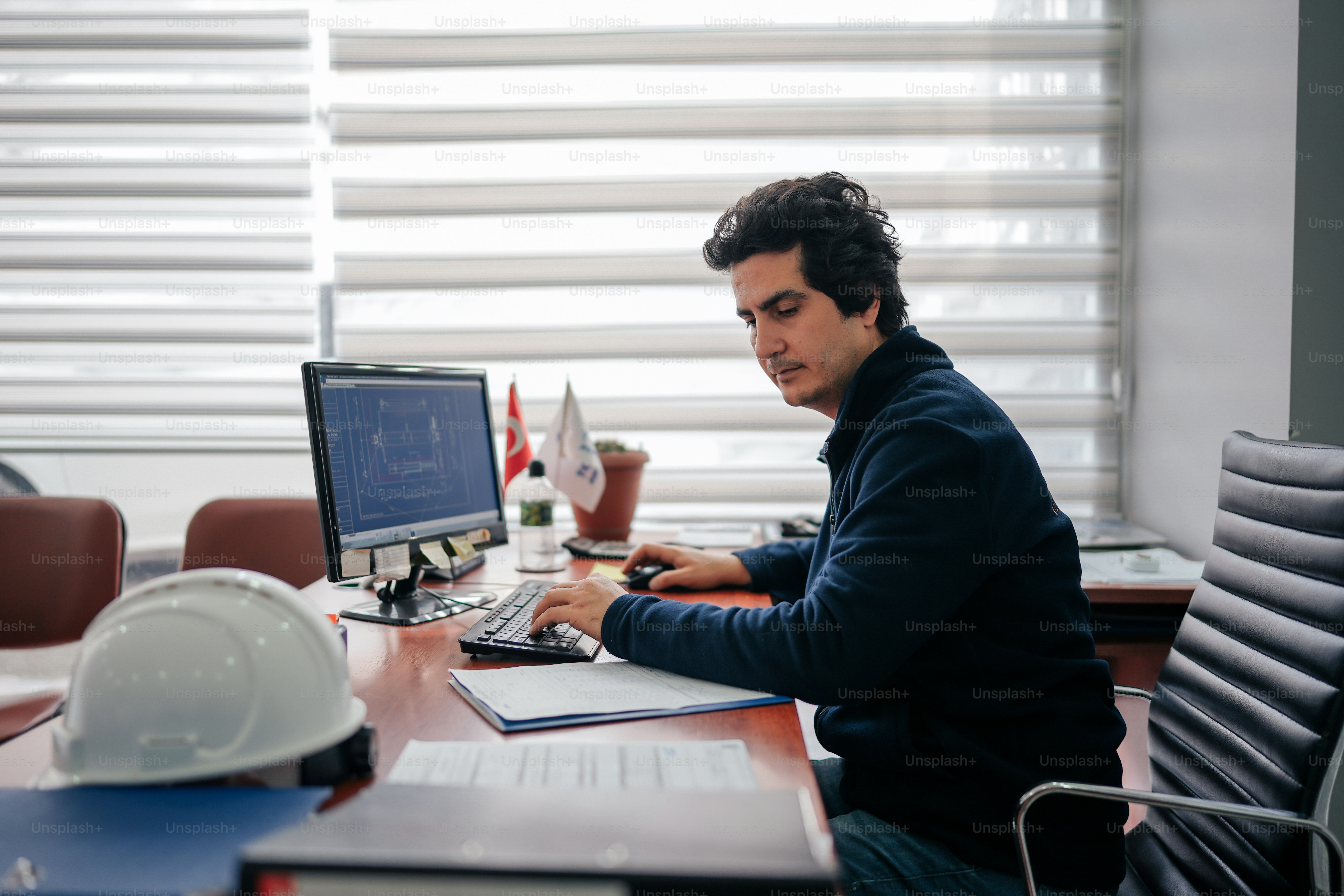 A man sitting at a desk using a laptop computer photo – Work desk Image ...